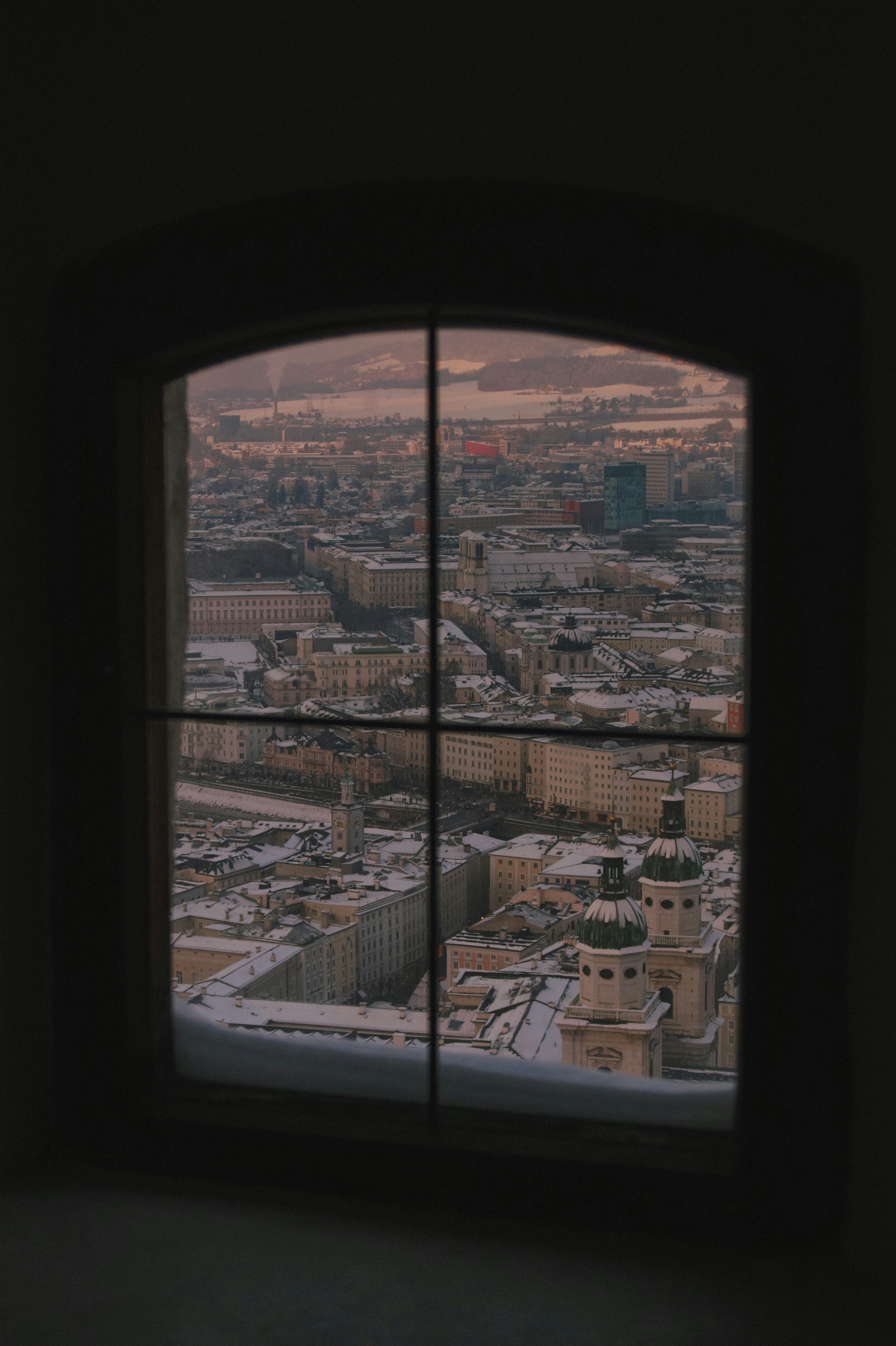 Through the Window: Snow-Kissed City at Dusk