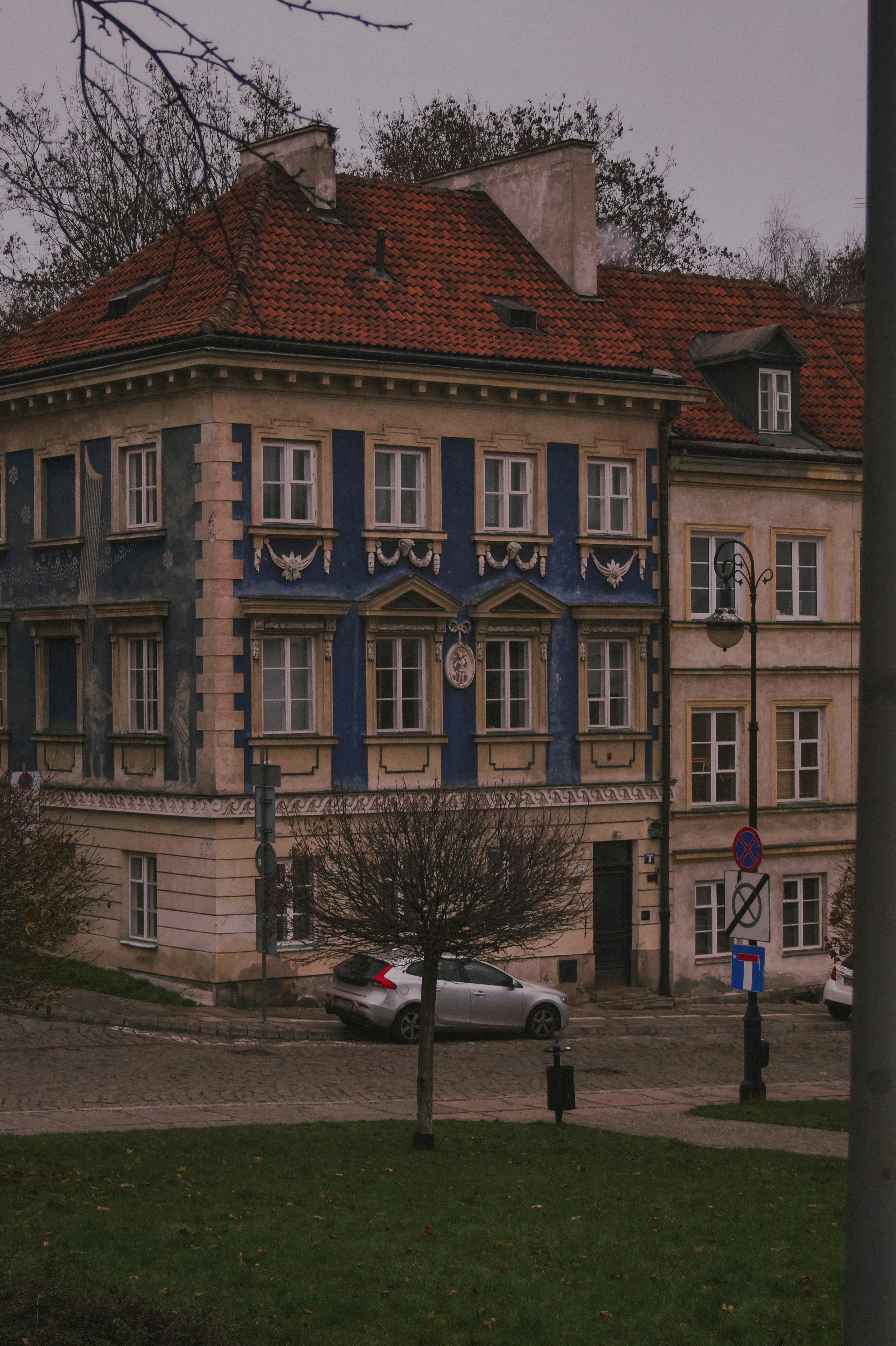 Historic building with blue and cream facade, featuring intricate architectural details and a clock, set against a moody, overcast sky.