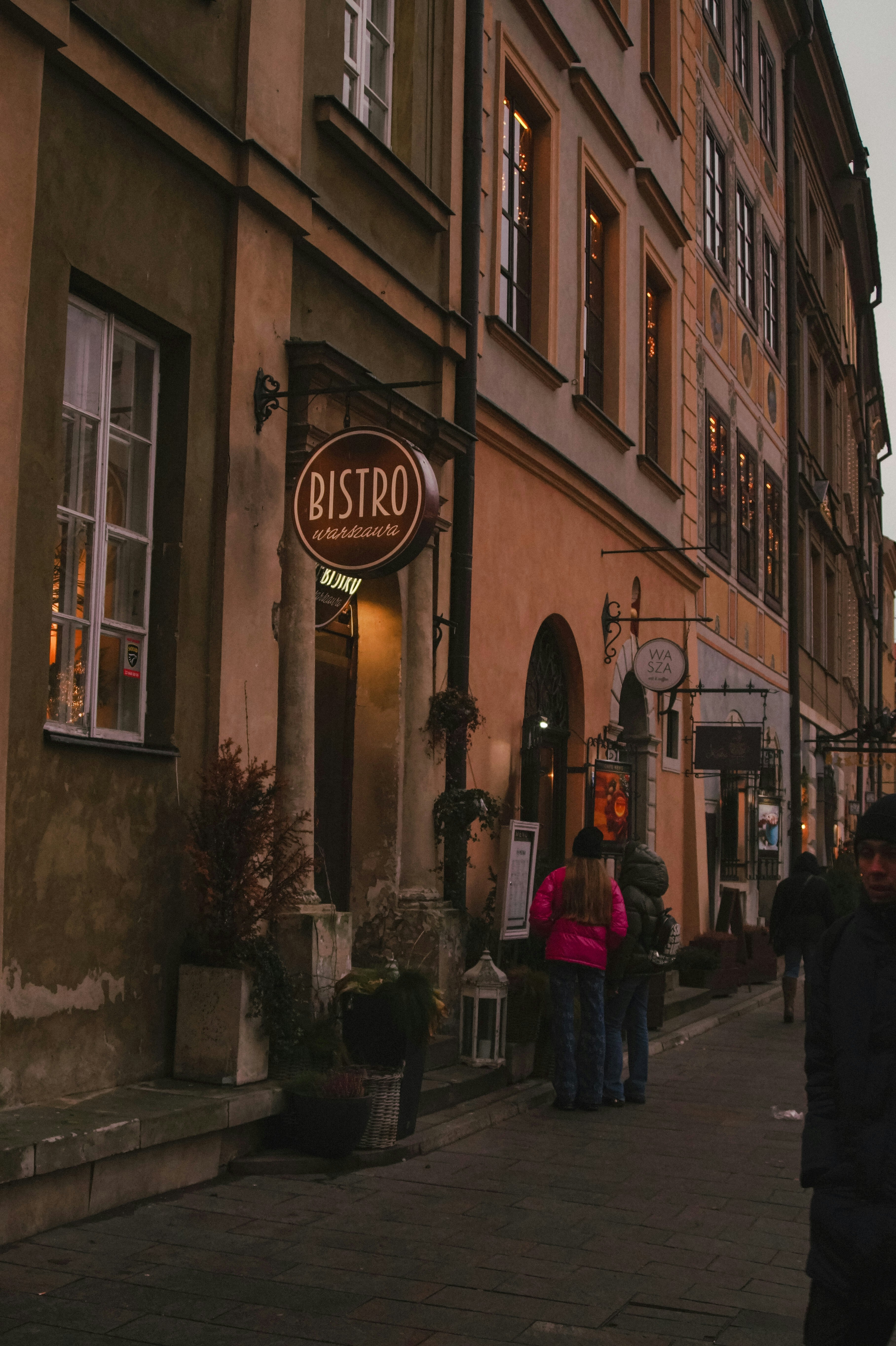 Evening Glow: Round Bistro Sign and Quiet Street Along a Cobblestone Lane