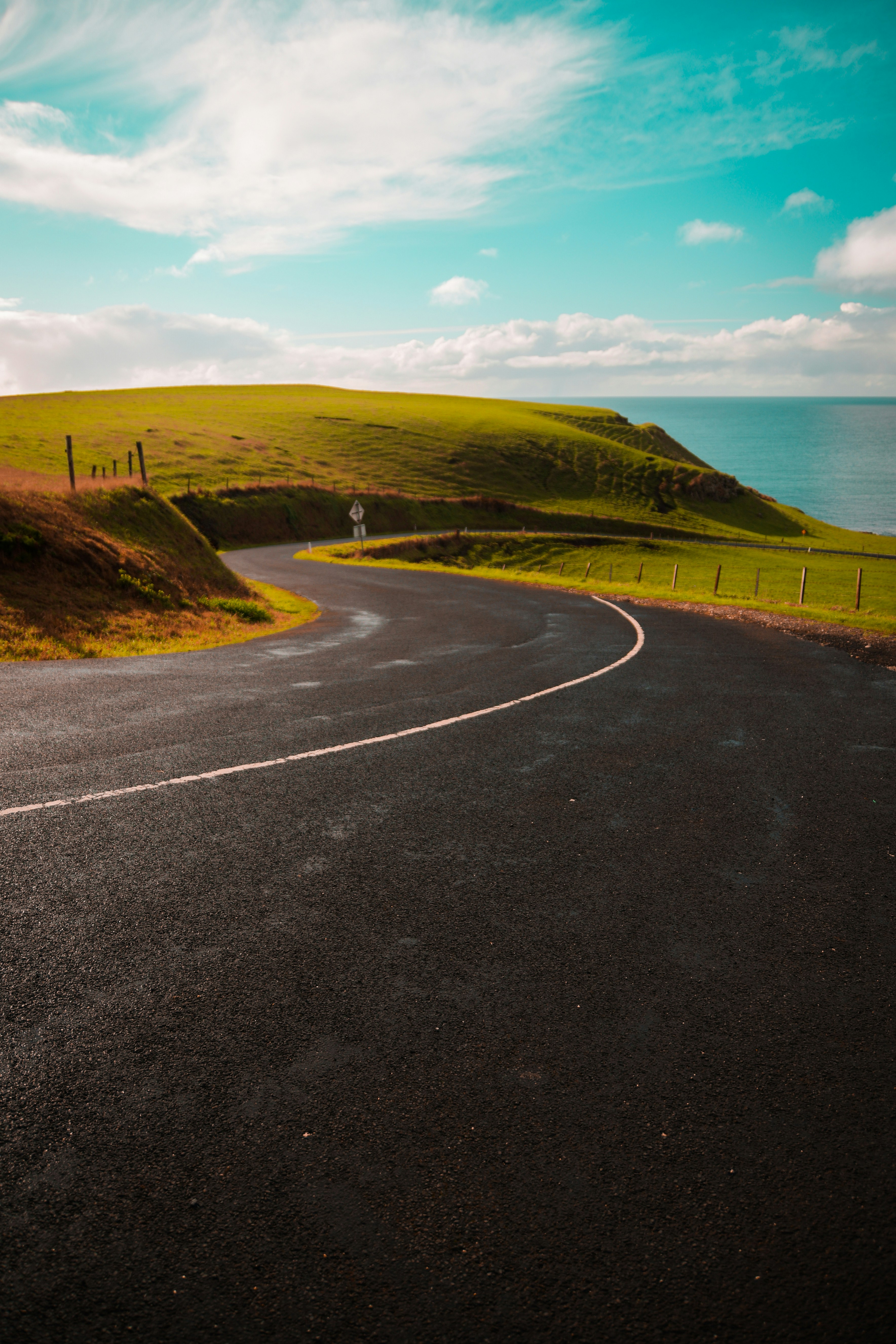 A curved road with a grassy hill in the background photo – Free ...