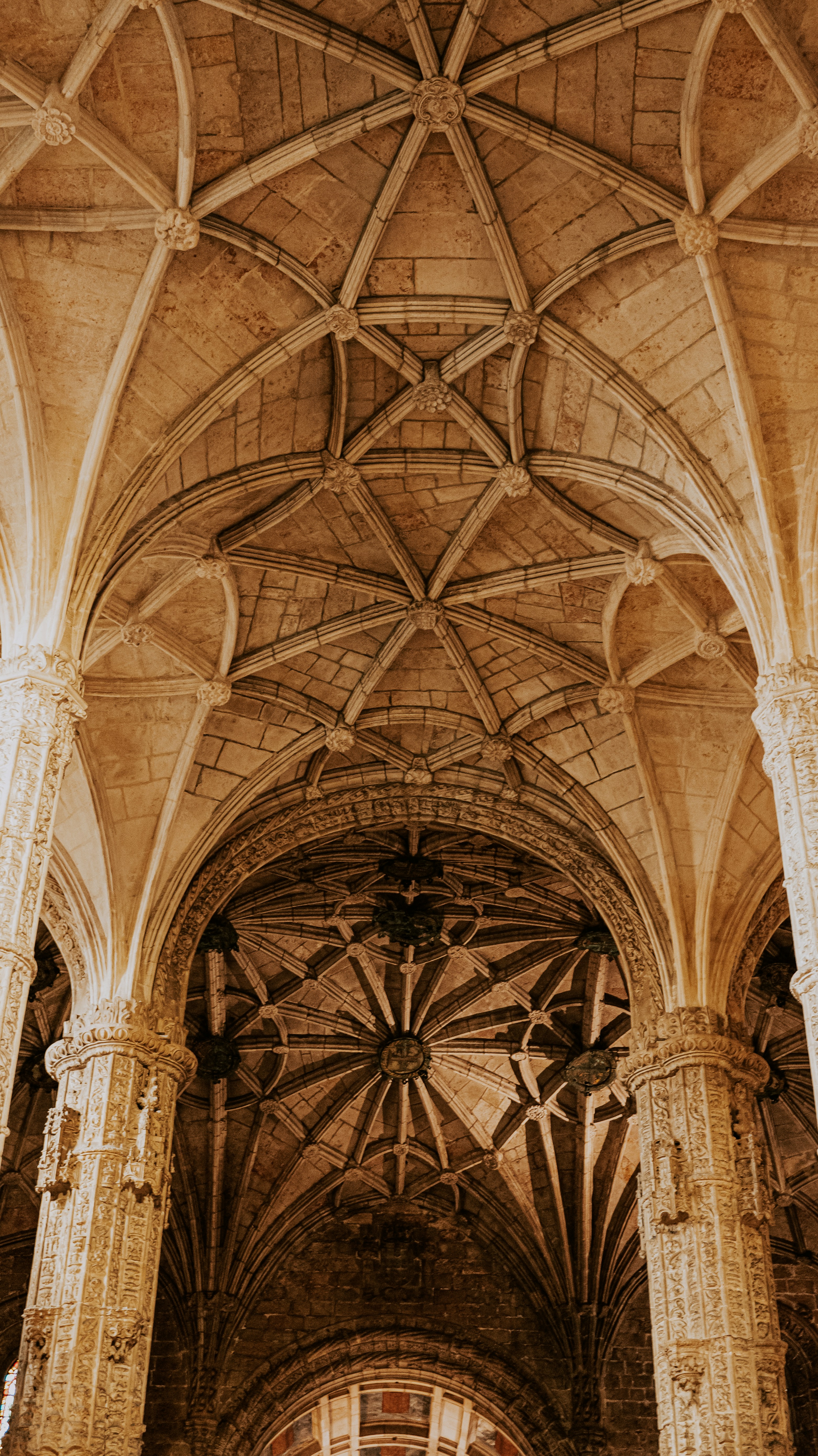 Intricate stone arches and detailed ceilings create a mesmerizing pattern in this historical architecture. The interplay of light and shadow enhances the structural beauty.