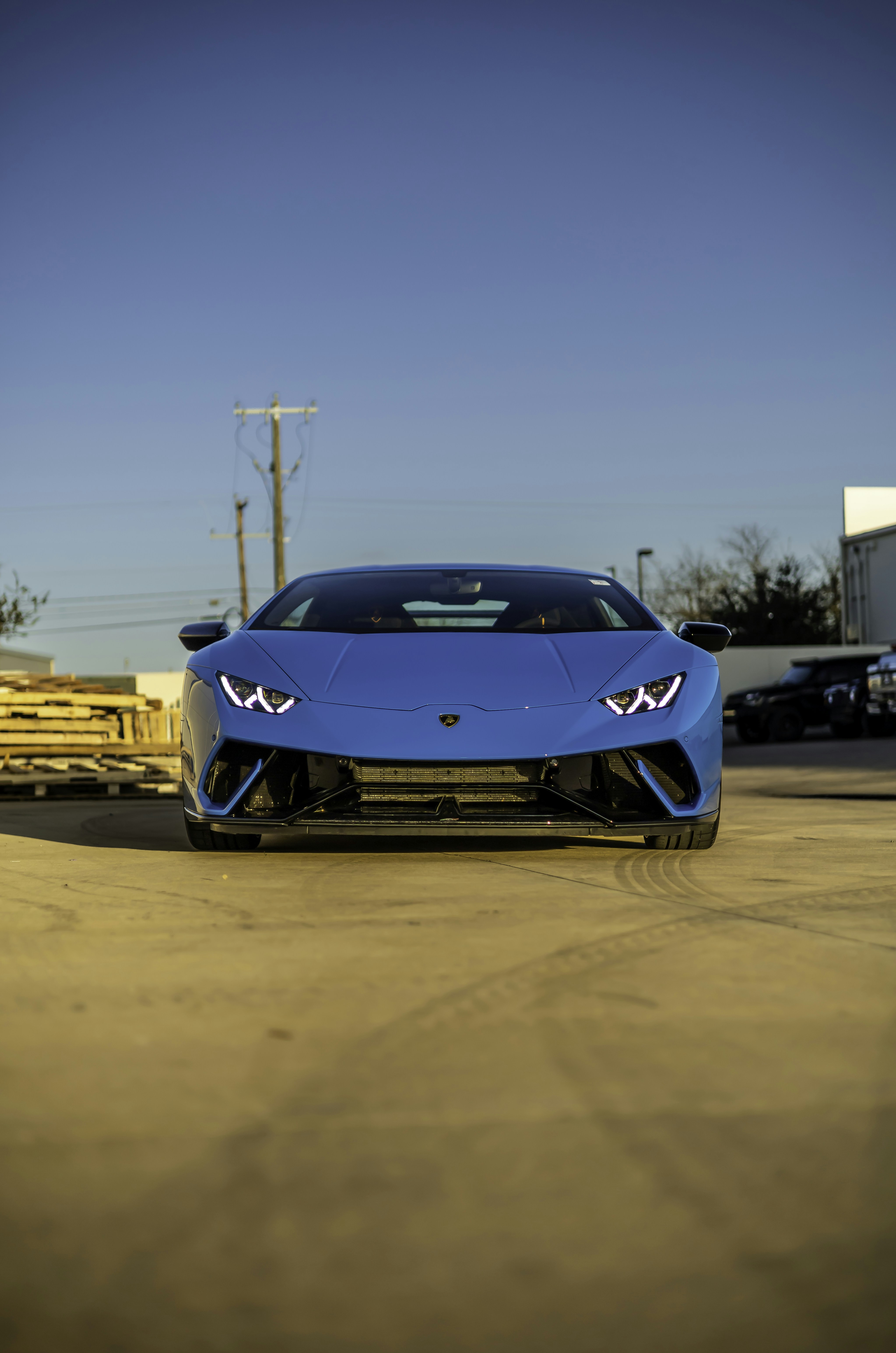 Blue Lure: A Lamborghini's Low-Angle Gaze in an Industrial Sunset