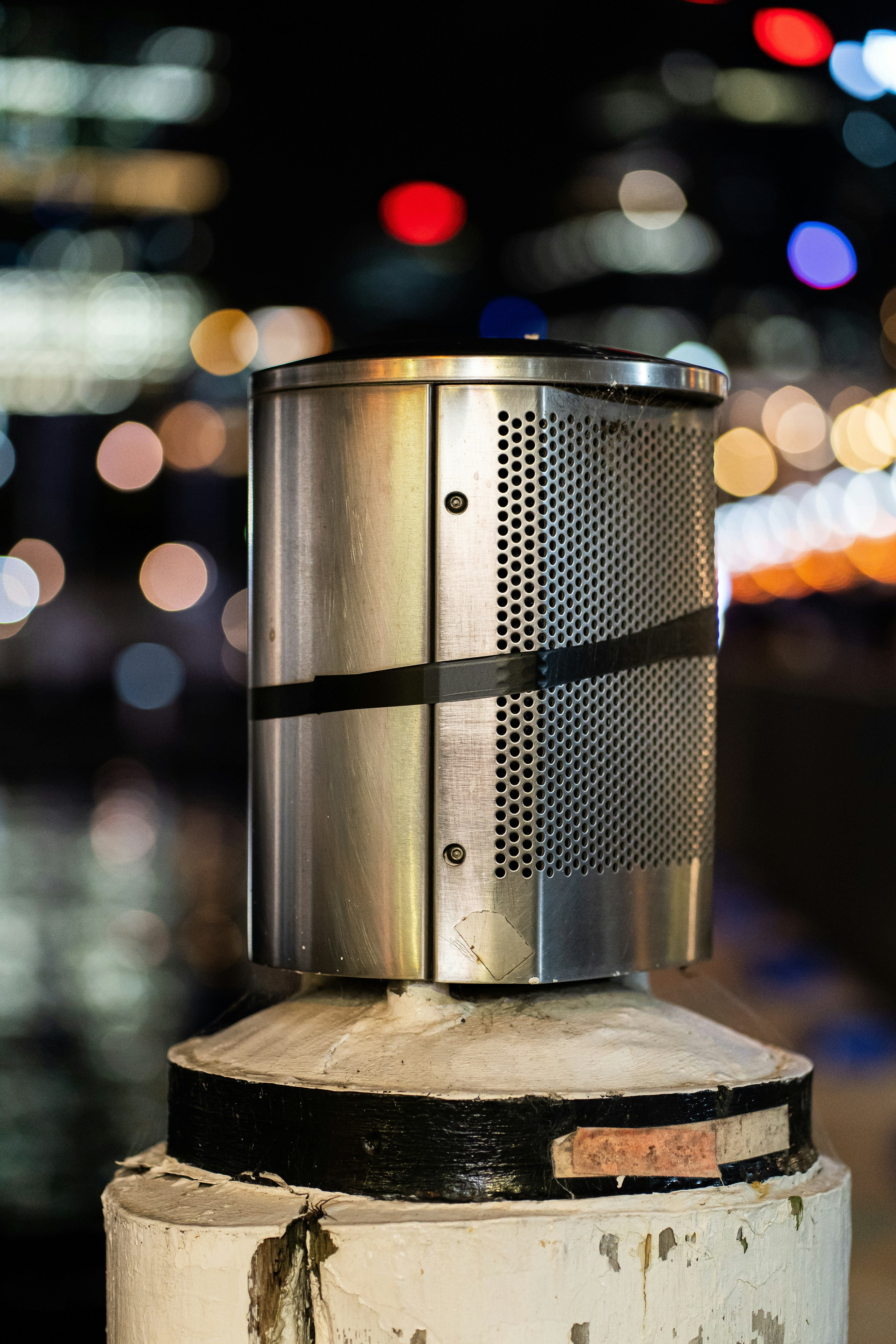 Night Pier: Stainless Post Against a City Blur