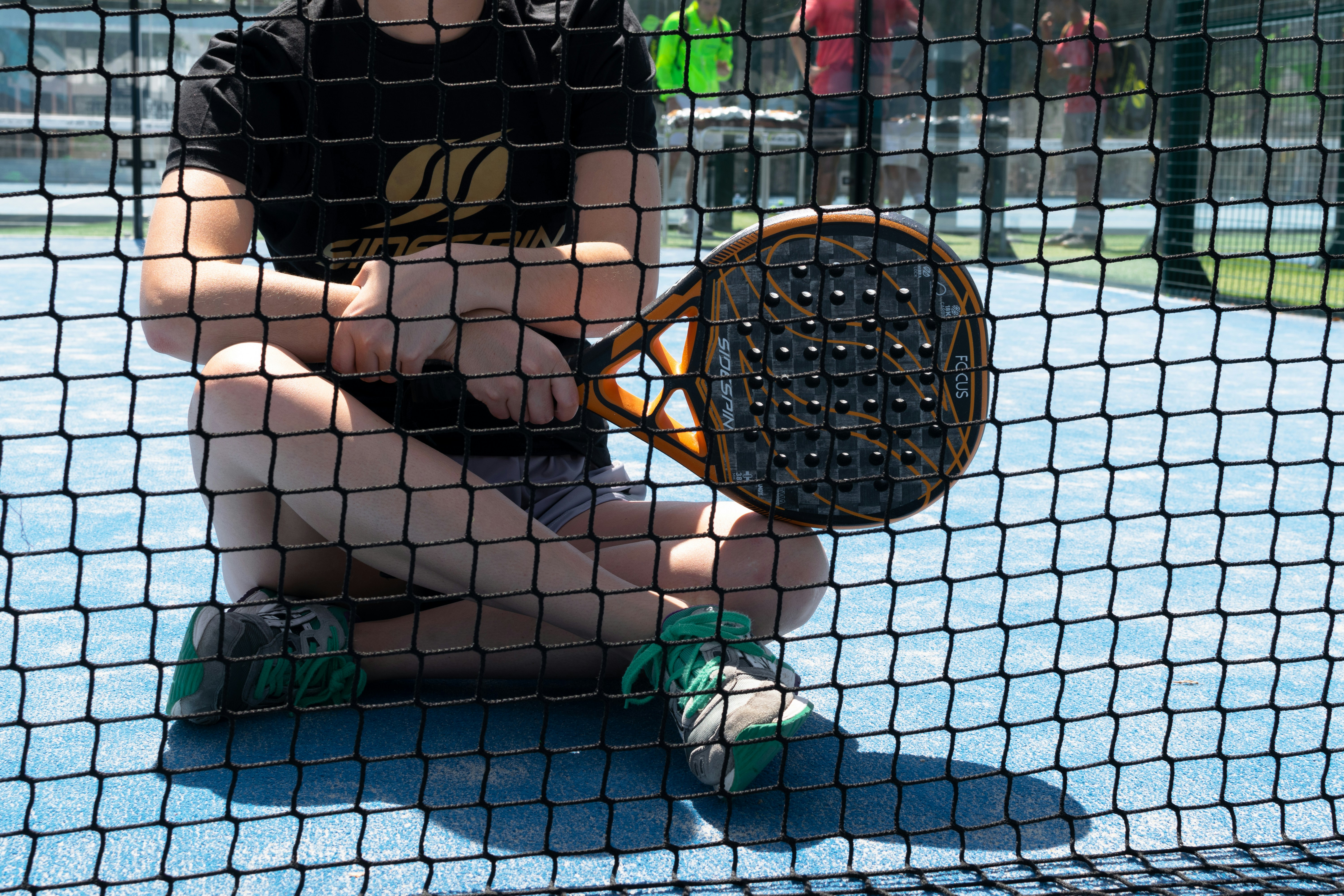 A young boy sitting on the ground holding a tennis racket photo – Free ...