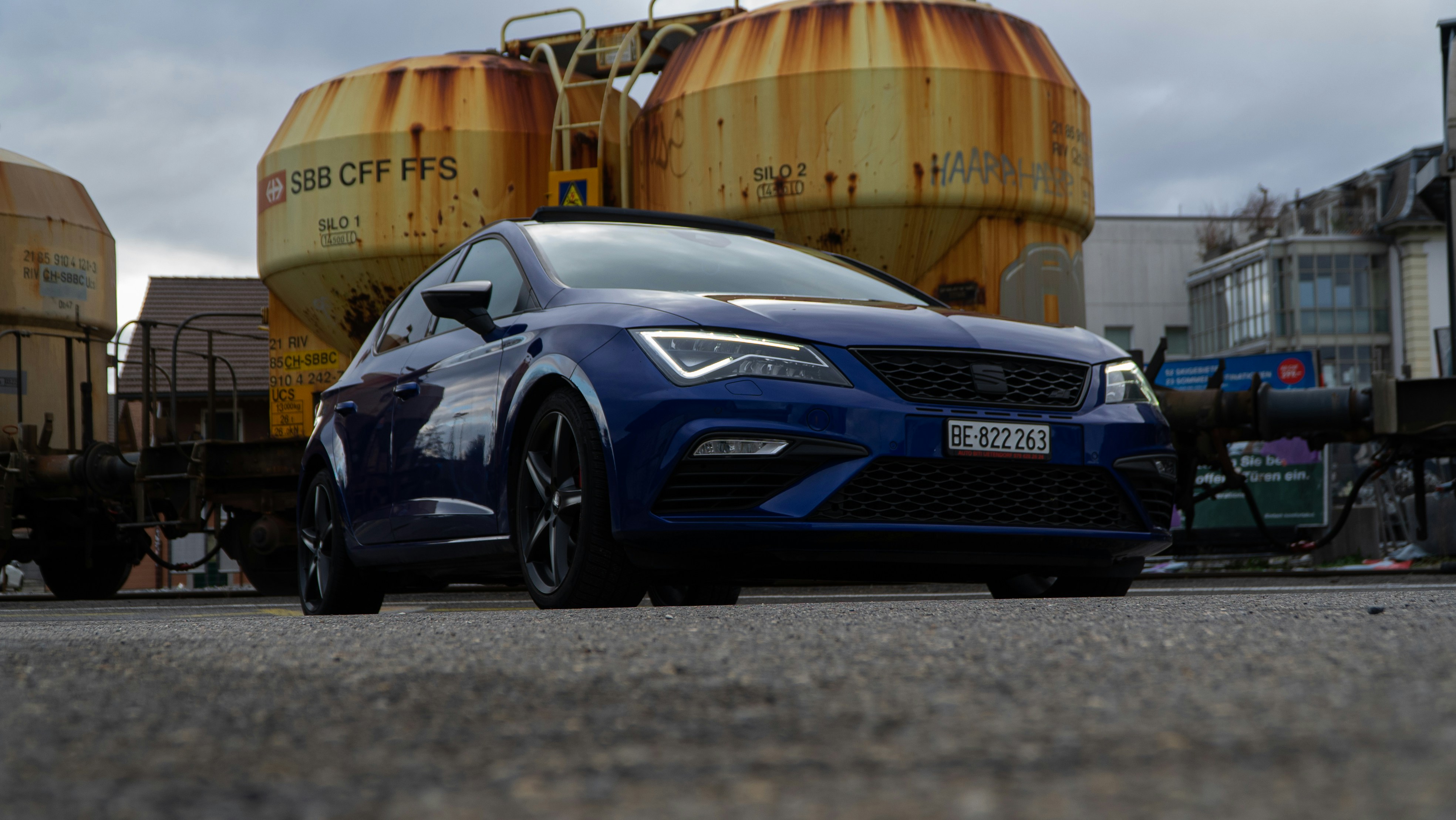 Urban Elegance: A Blue Machine Amidst Industrial Giants