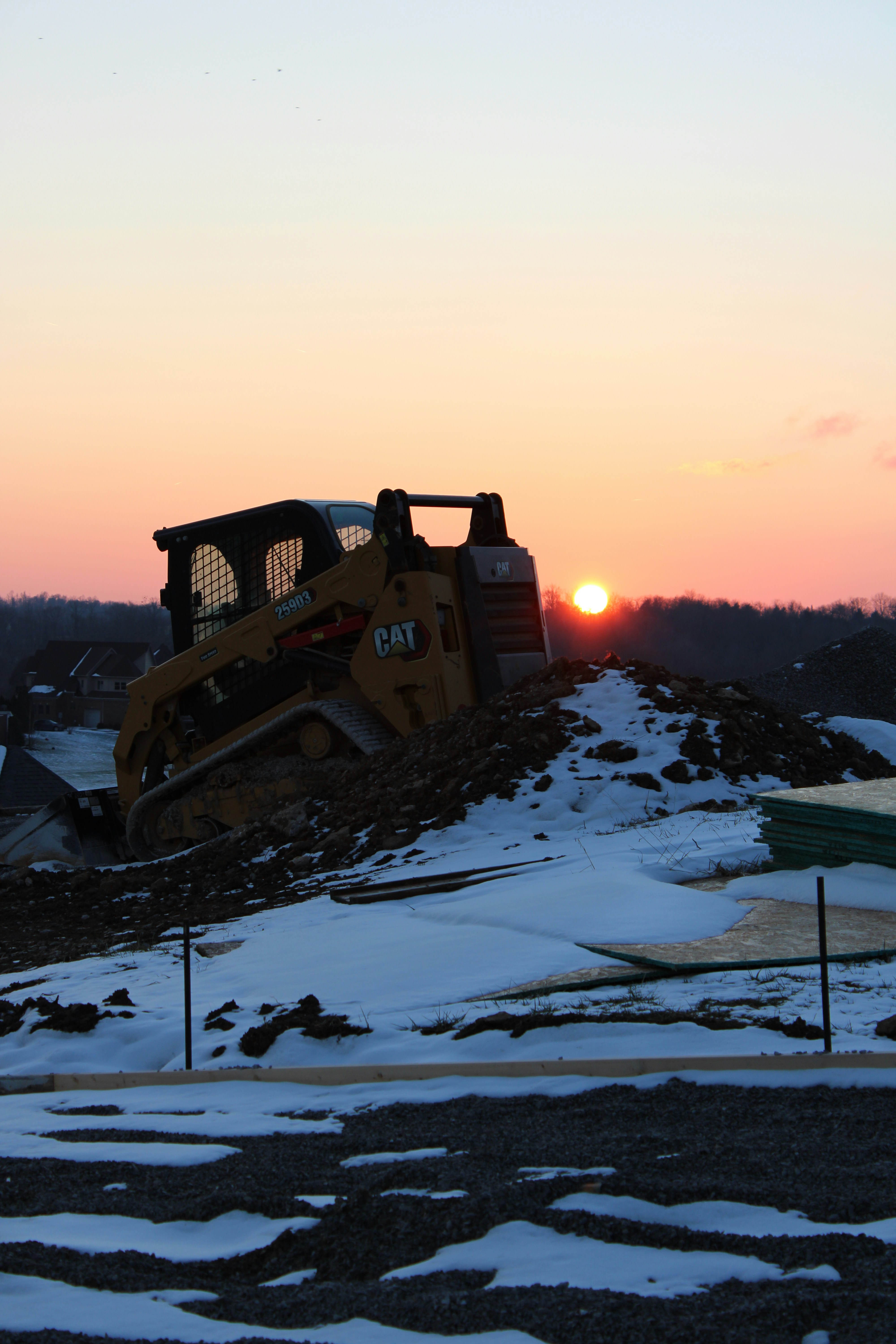 Sunset Summit: CAT Bulldozer Rises Over a Snow-Capped Construction Mound