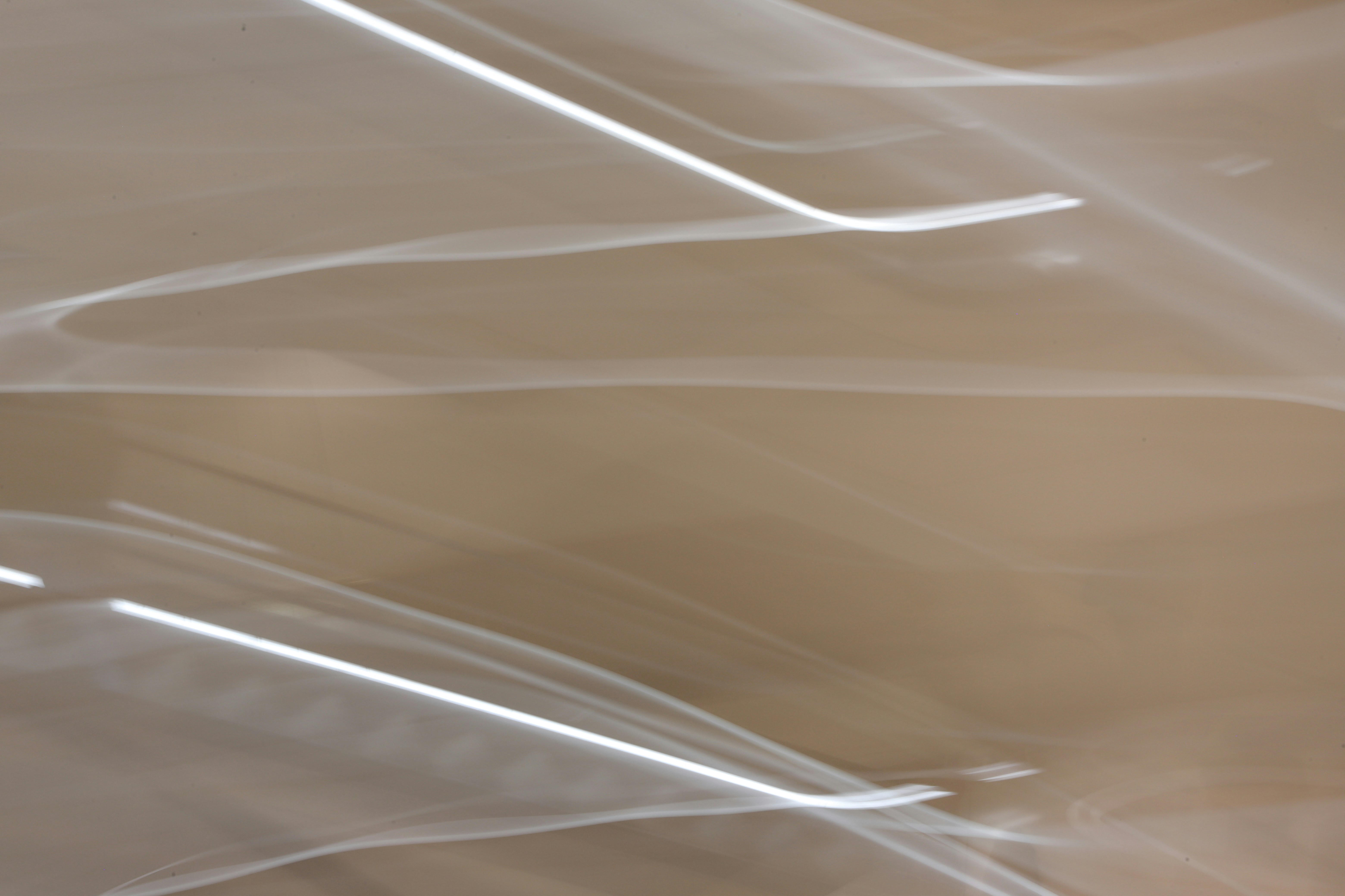 Abstract composition featuring flowing transparent lines against a soft beige background, evoking a sense of movement and fluidity.