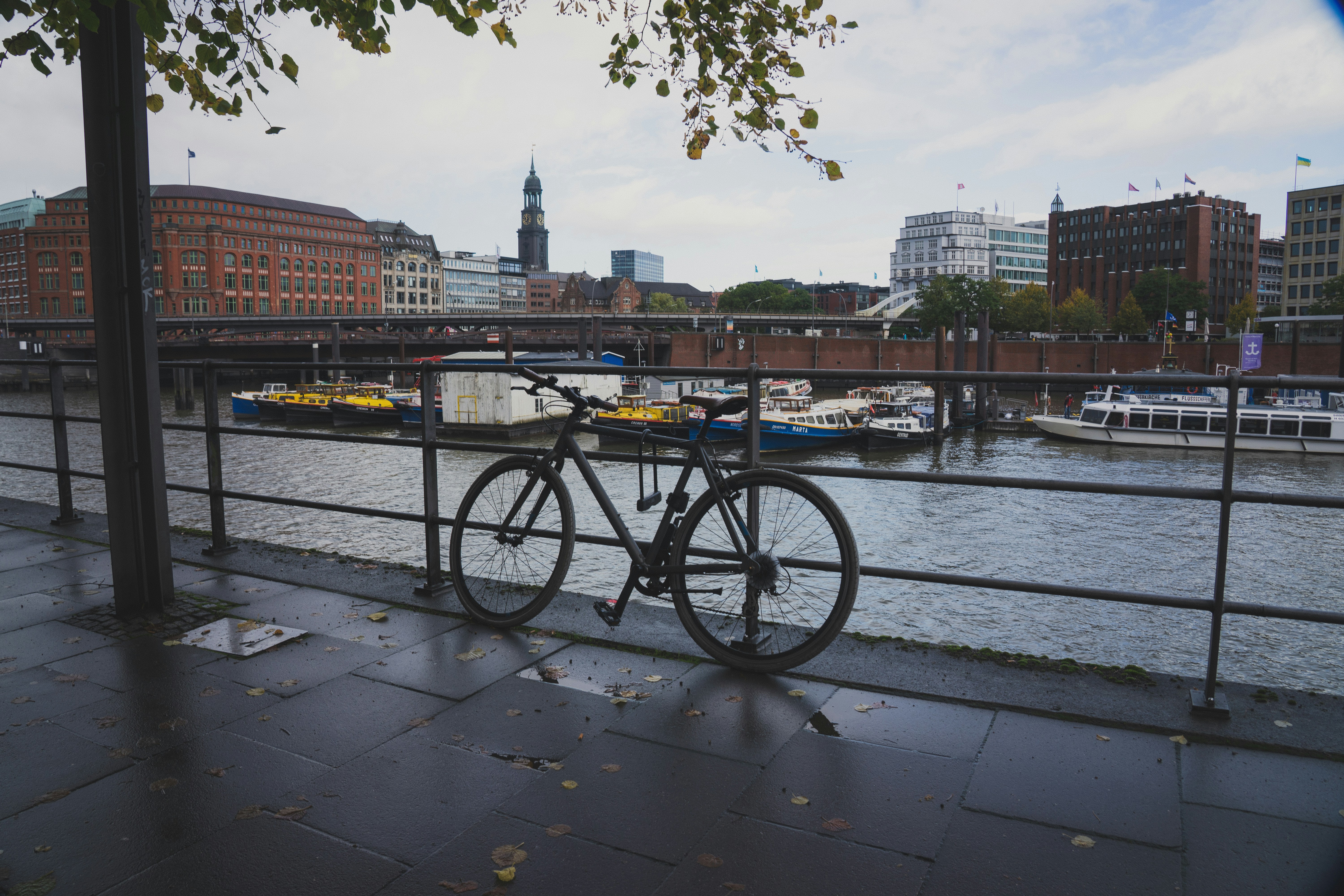 Riverside Pause: A lone bicycle foregrounds a harbor of boats and brick skyline