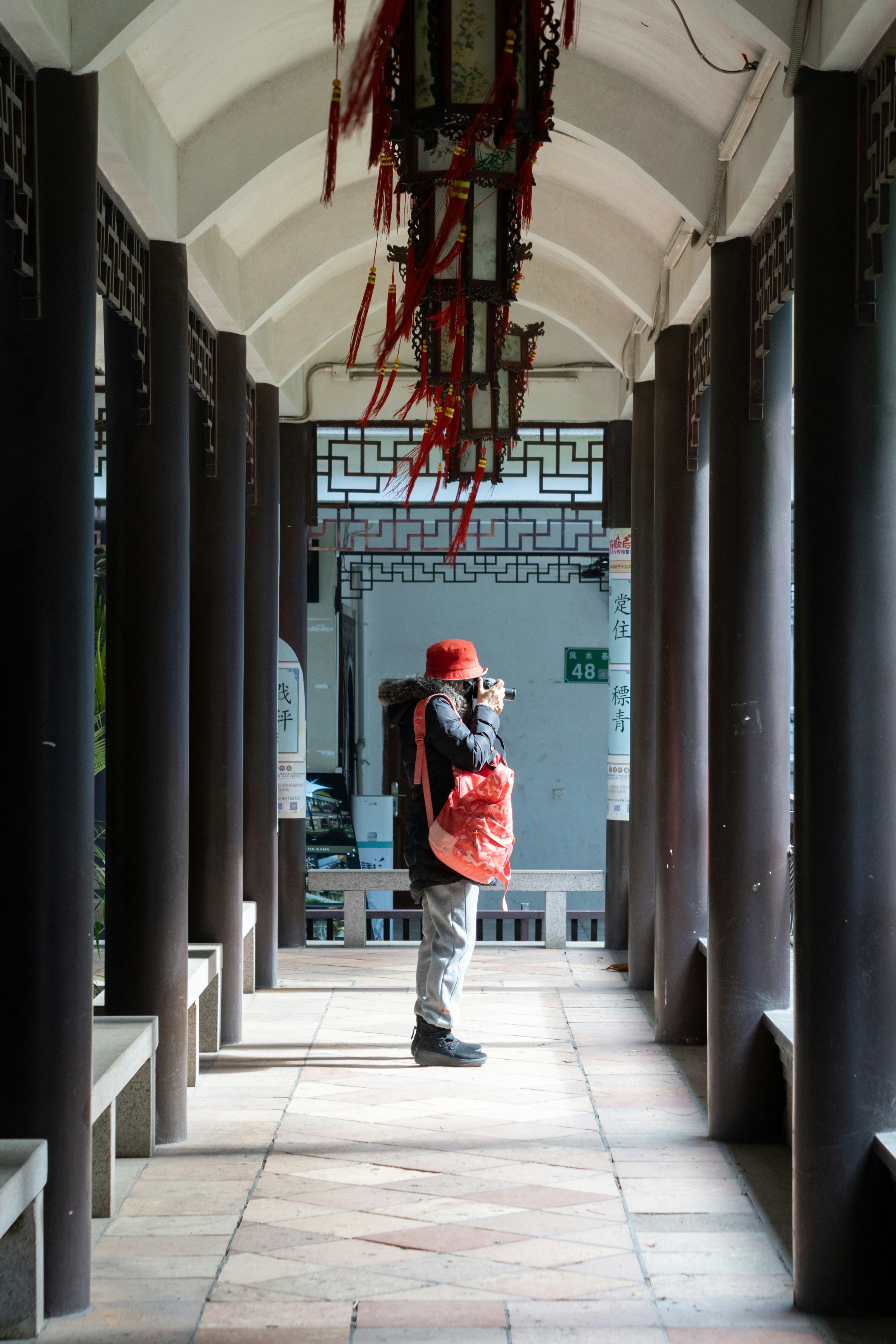 a man with a red backpack standing under a covered walkway