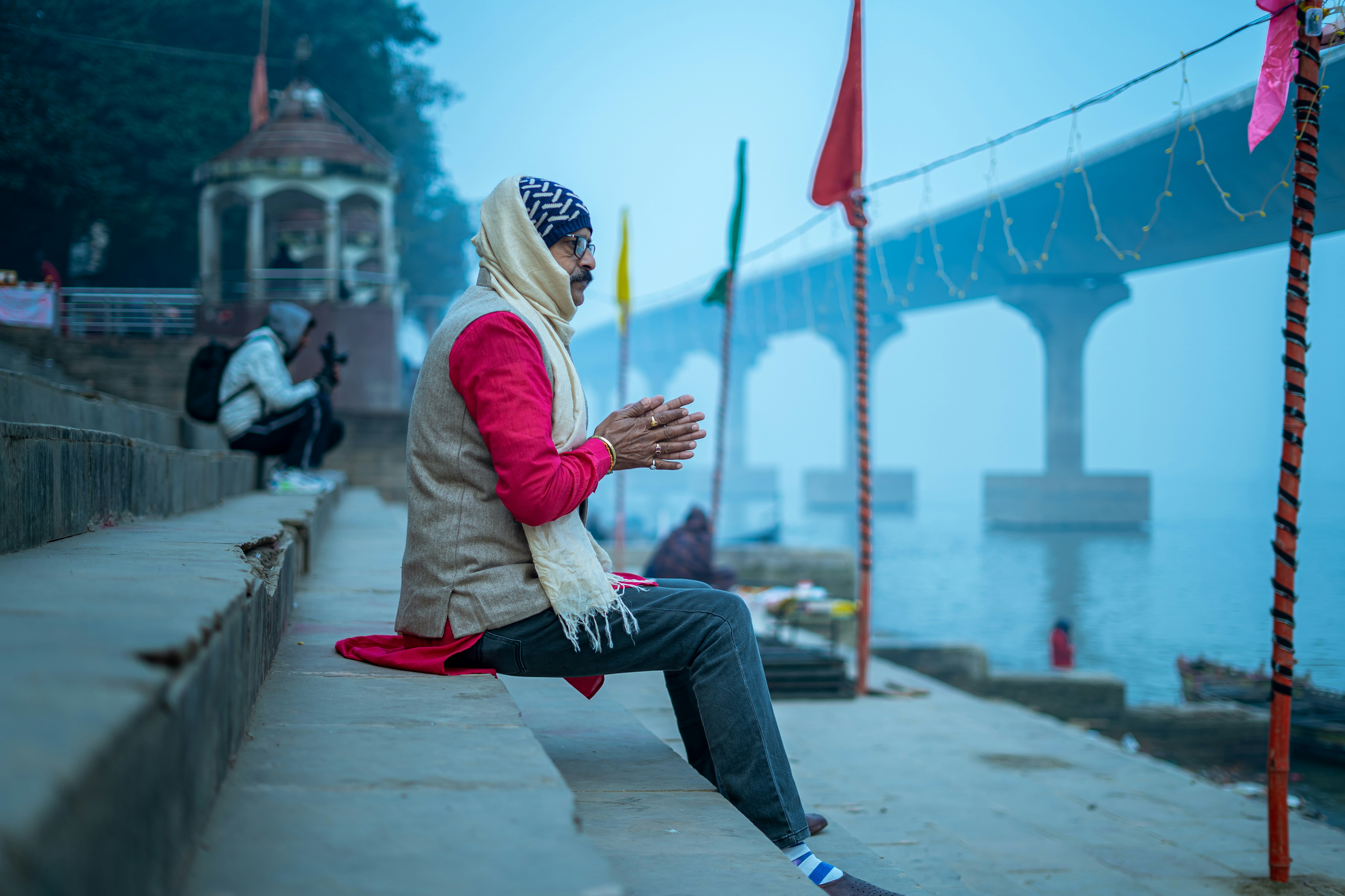 A person sitting on a ledge with a bridge in the background photo ...