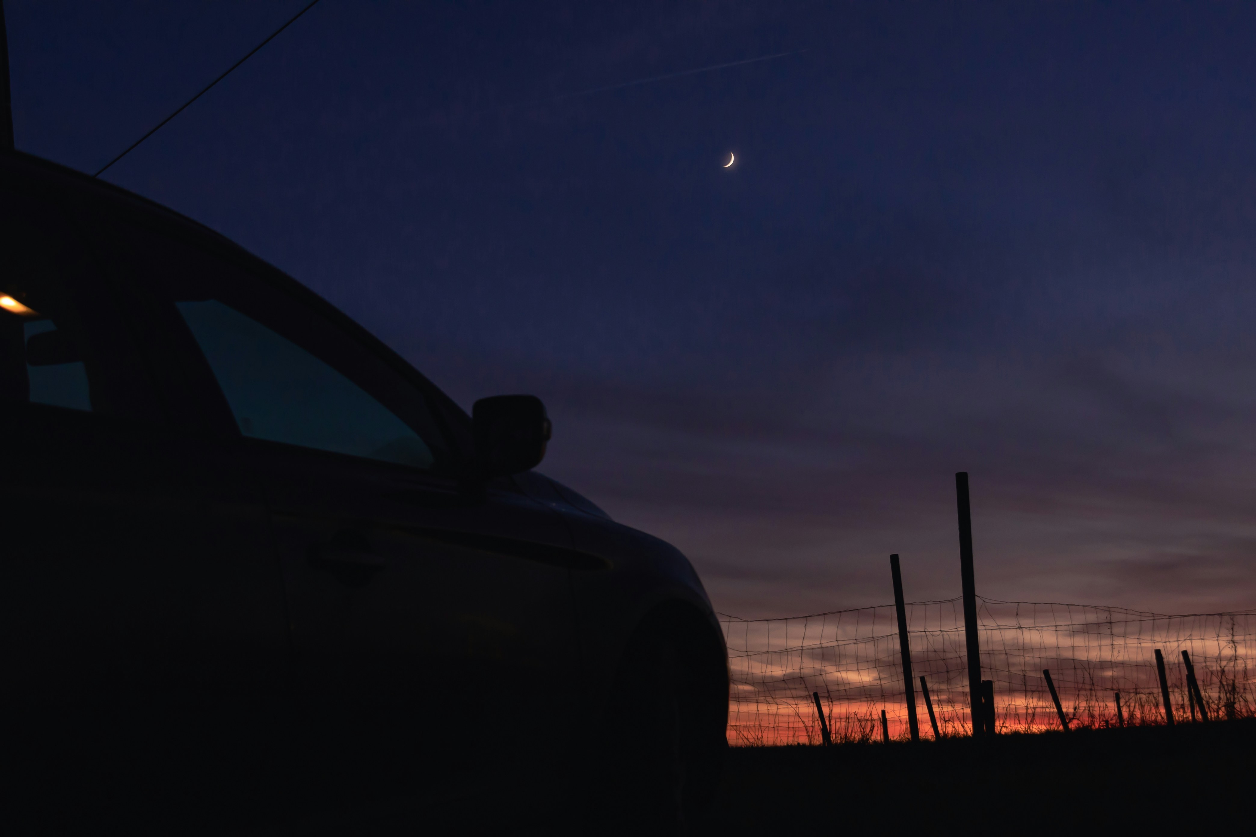 Crescent Moon Over a Quiet Car Silhouette at Dusk