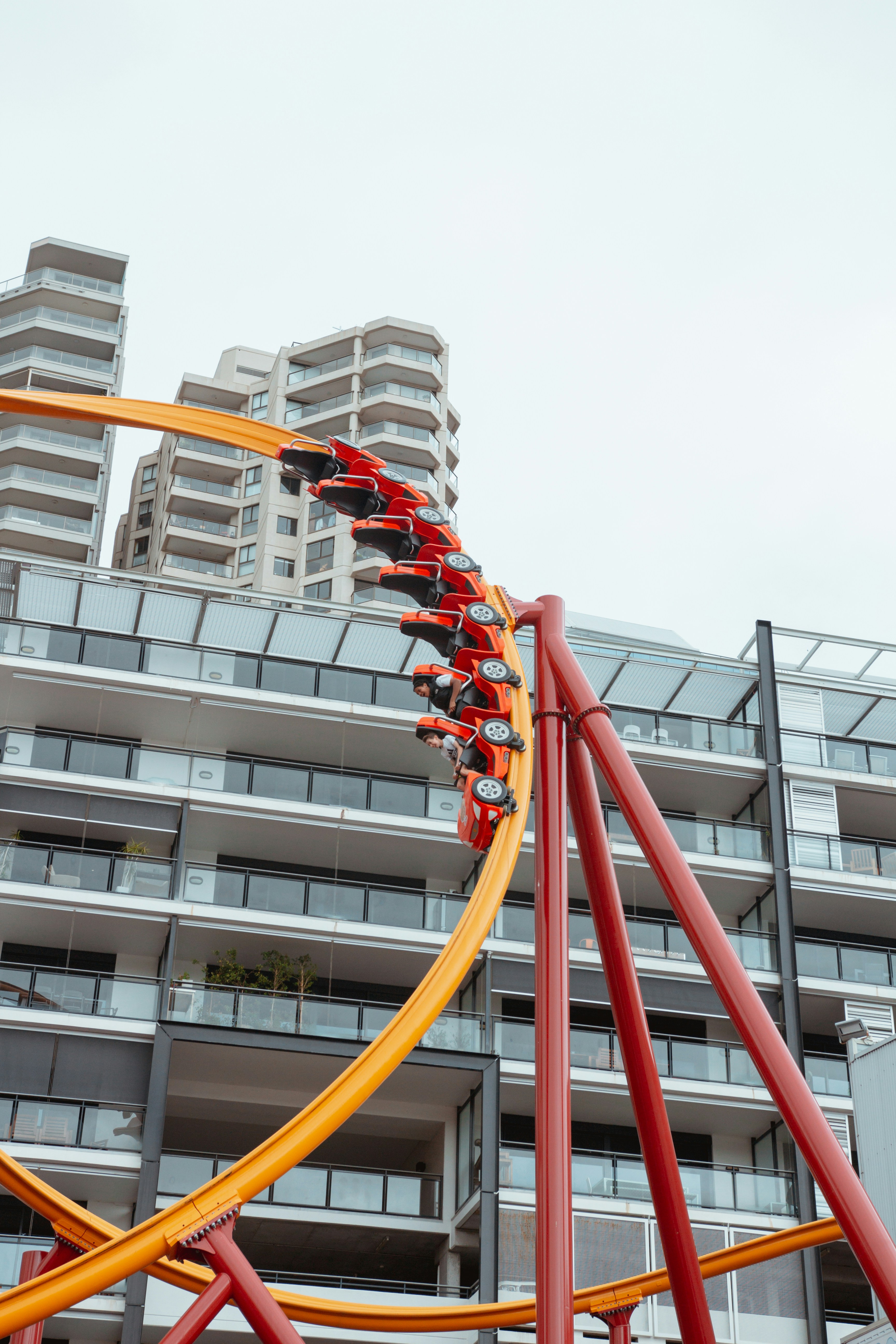 Circular ride in the city: a roller-coaster of orange and red against modern balconies