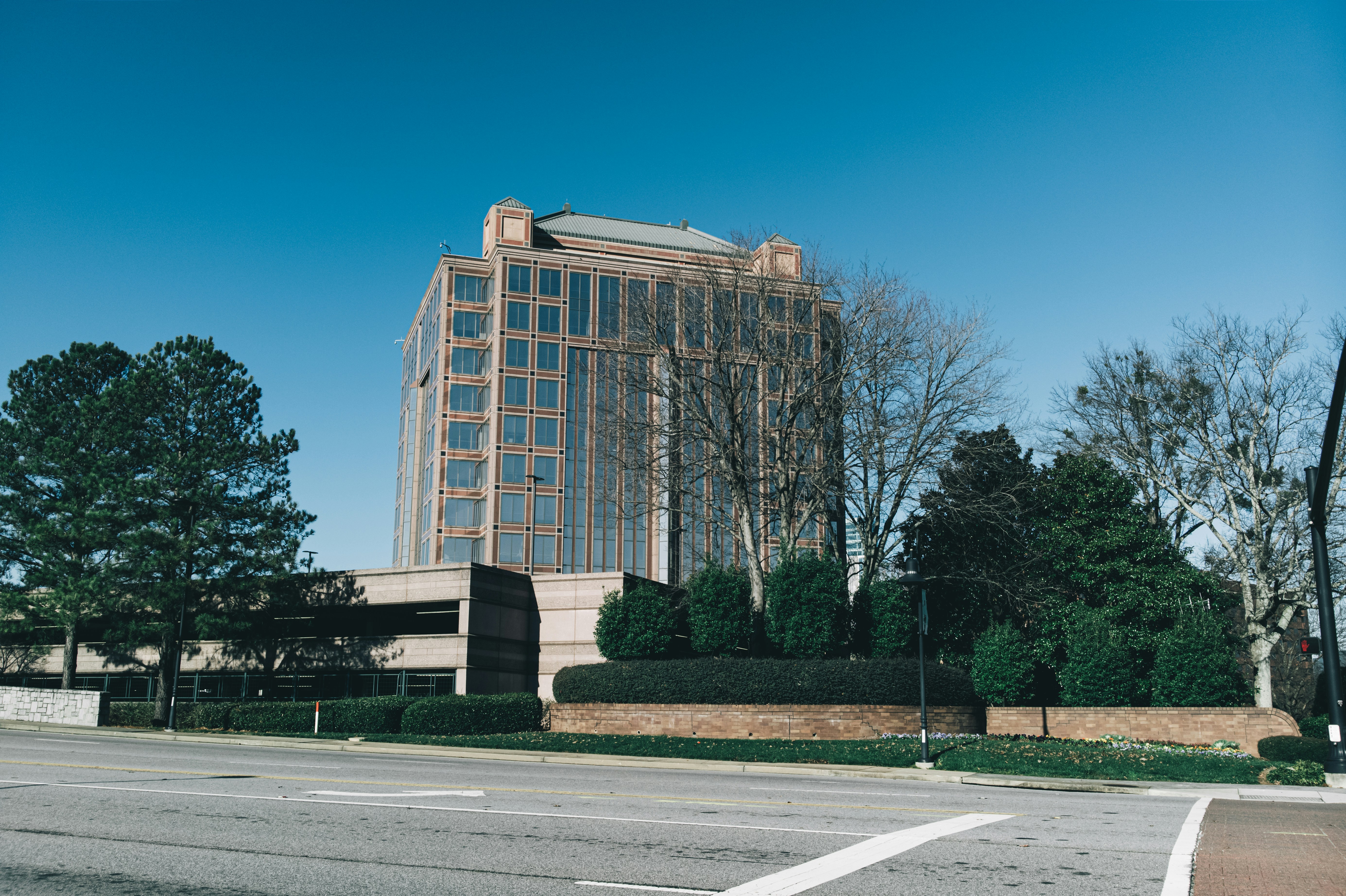 Contemporary building rising above a landscaped area with lush greenery and clear blue skies.