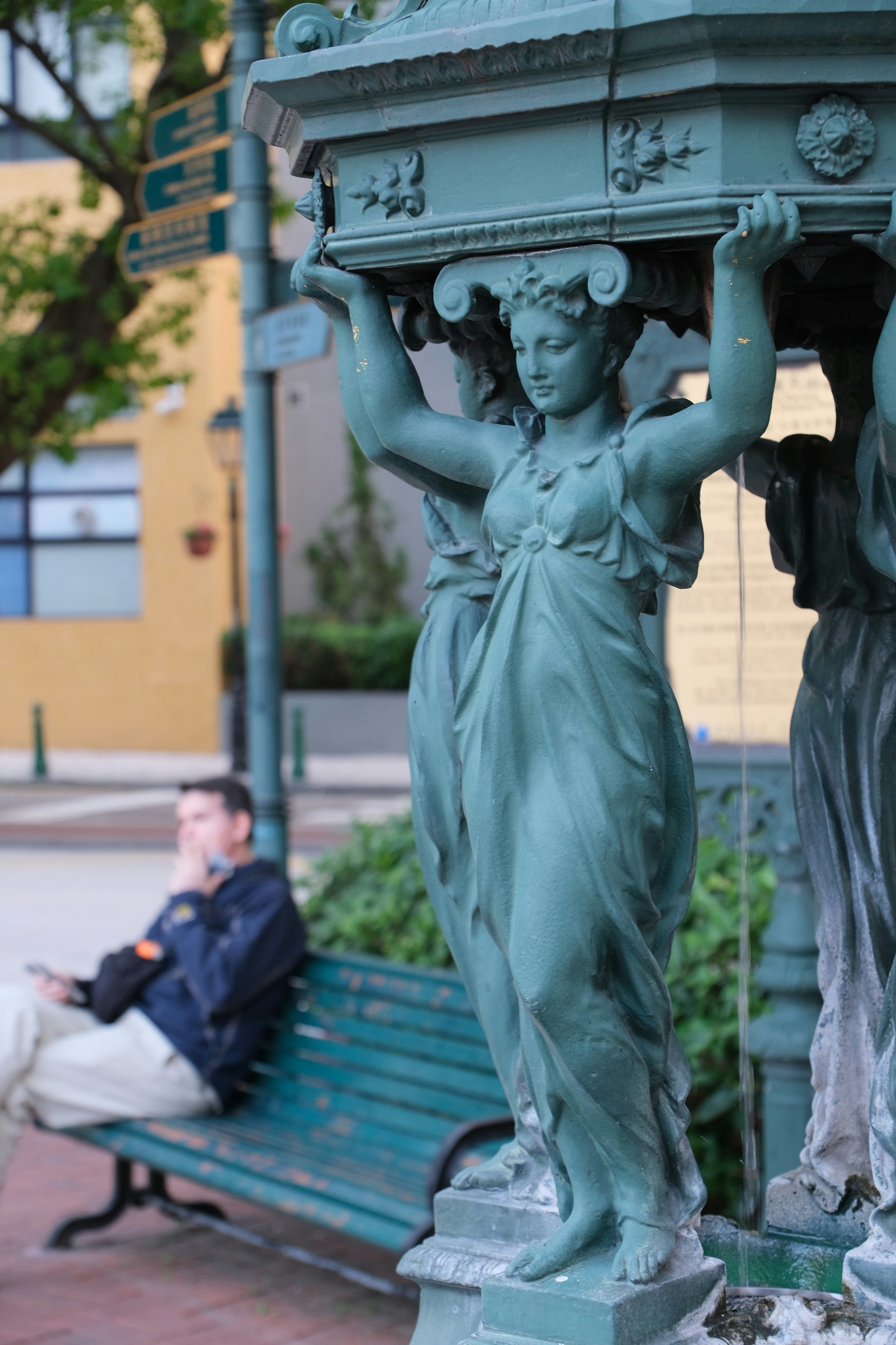 Teal-Tinted Figures: A Quiet City Fountain Among Passersby