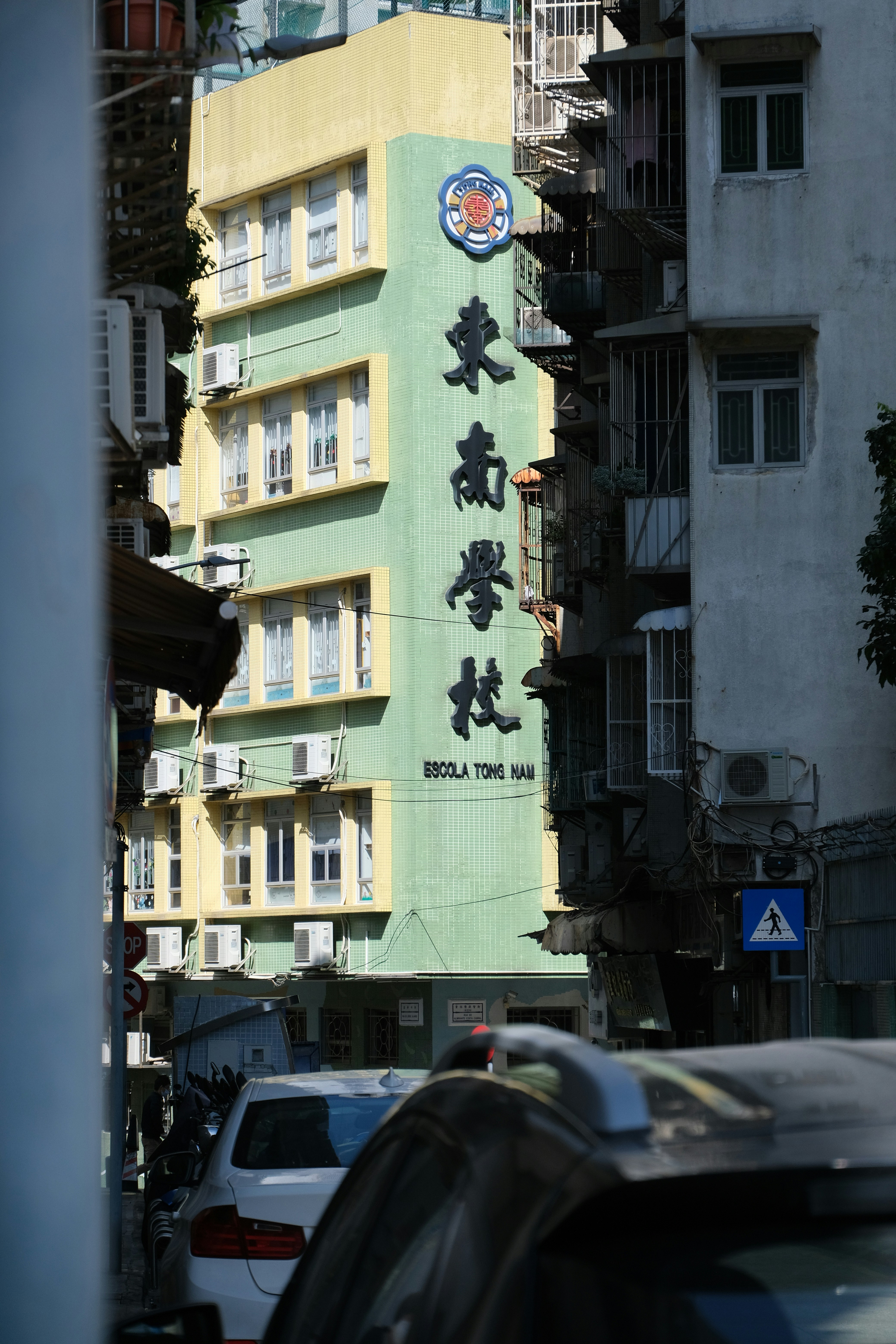 Pastel Highrise Schoolfront: Bold Vertical Script in a Narrow Street