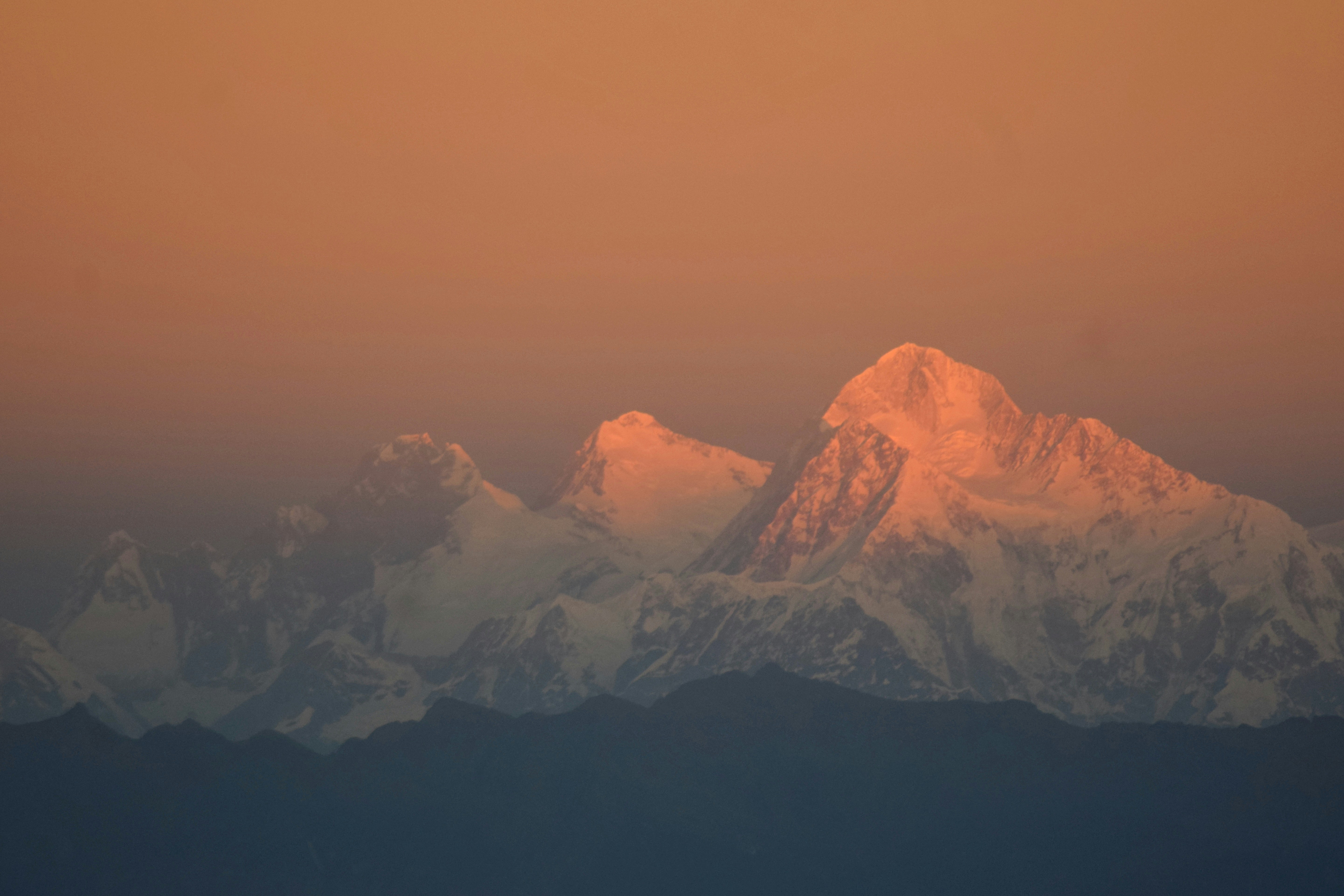 First rays from the sunrise illuminate the peaks of Mt. Makalu, Mt. Everest and Mt. Lhotse. Picture taken from Sabargram capsite, Sandakphu trek | a view of a snow covered mountain at sunset