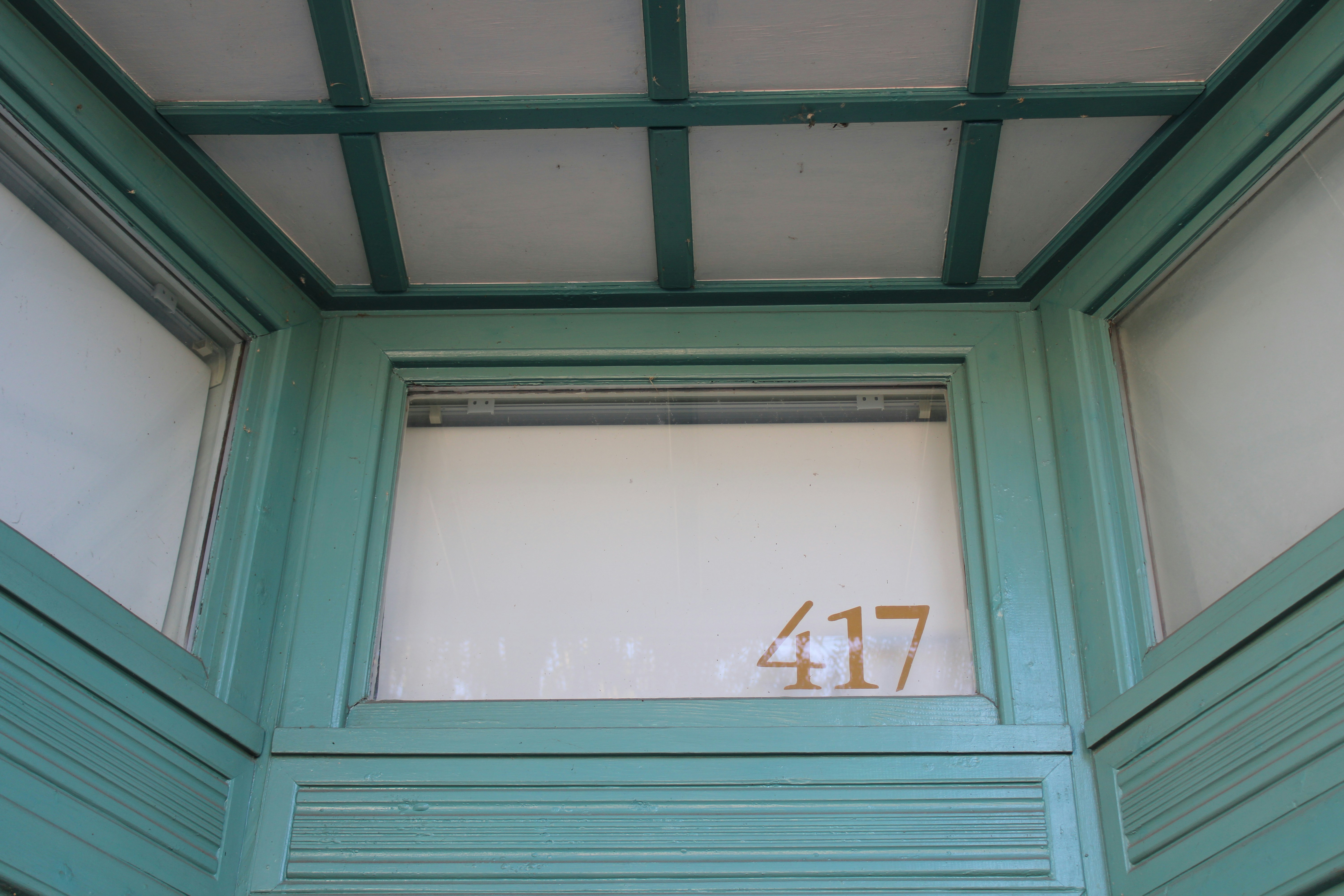Teal-Framed storefront nook with the number 417 in a sunlit window