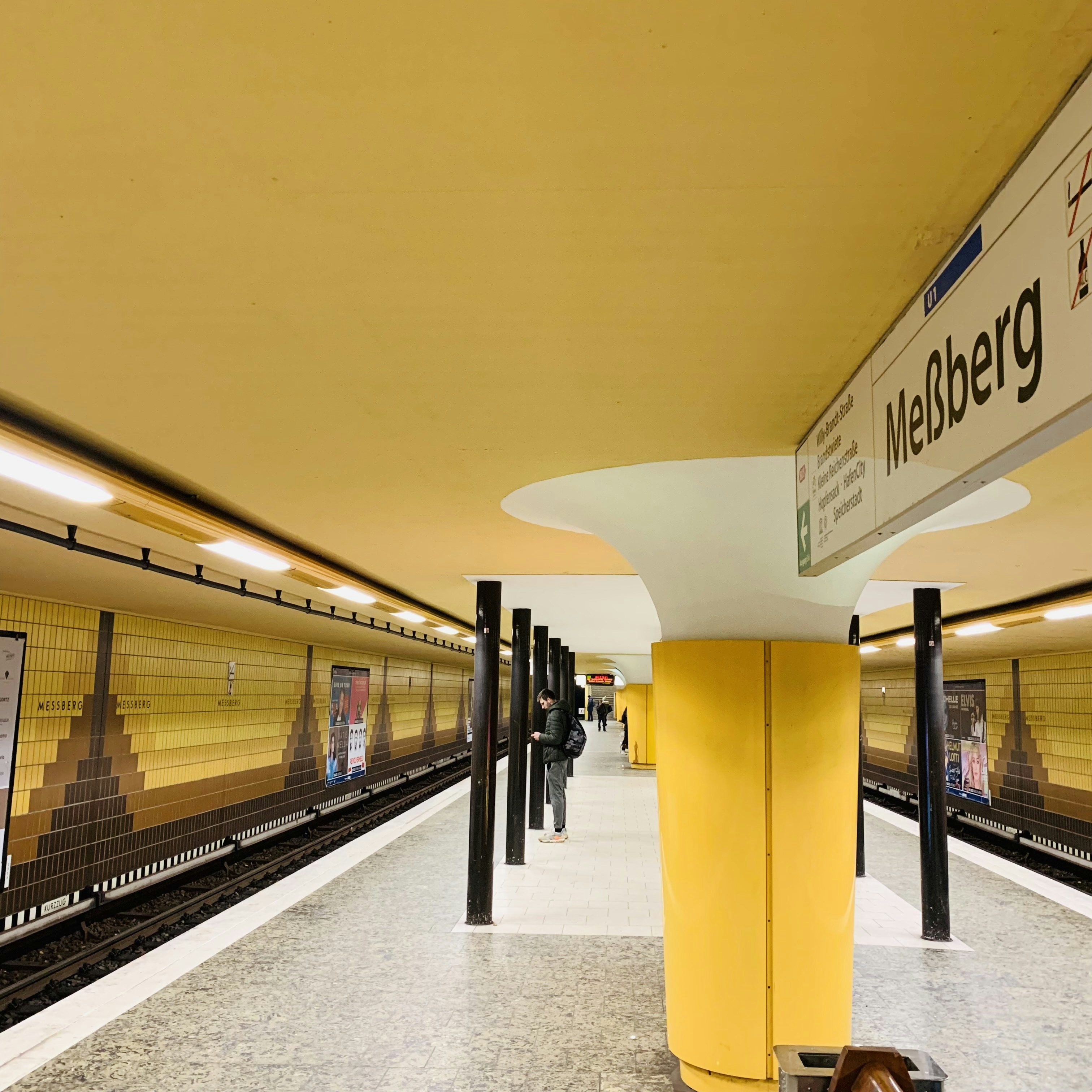 A subway station with a sign and a woman sleeping on the floor photo ...