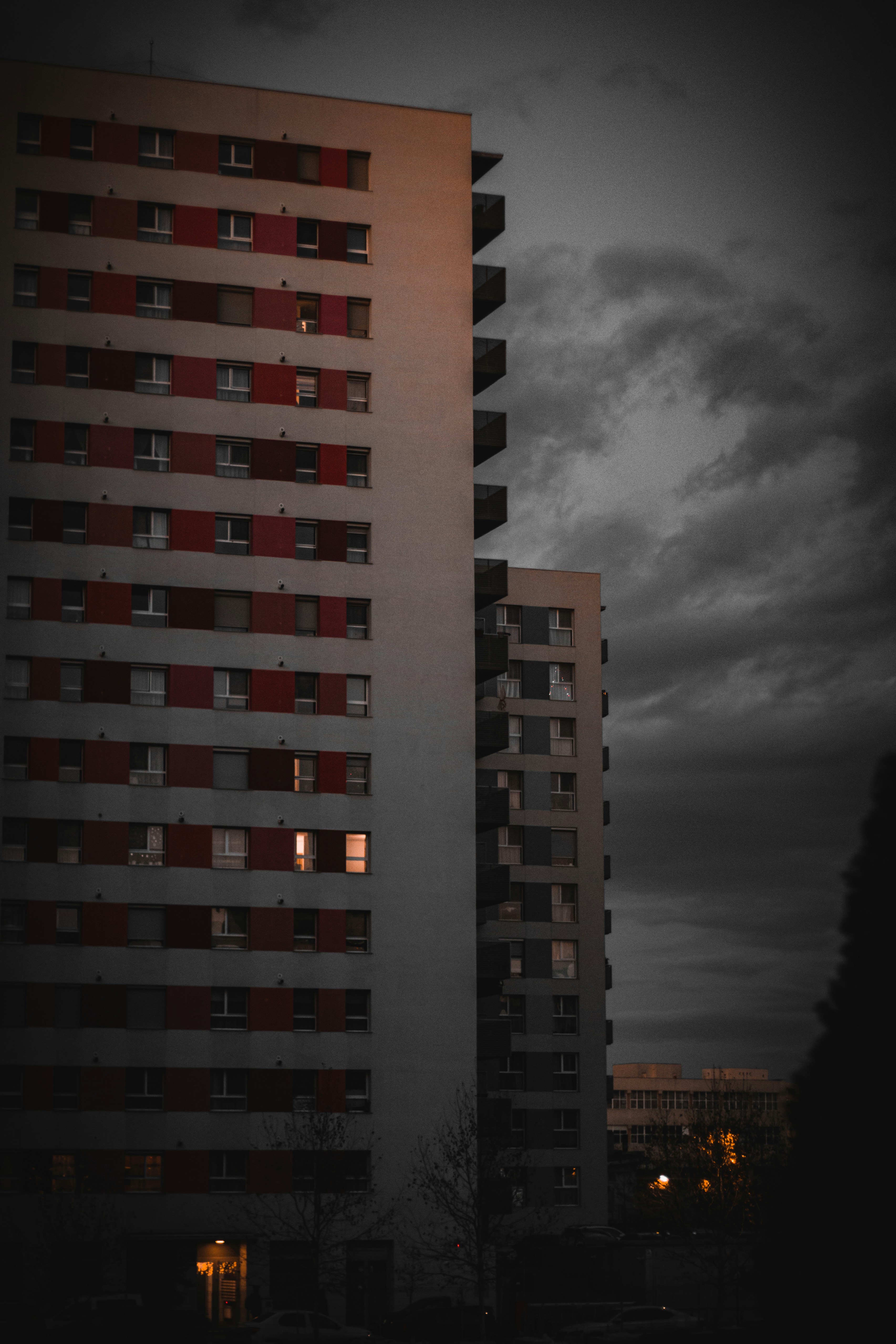 High-rise apartment buildings with illuminated windows against a dramatic sky at dusk.