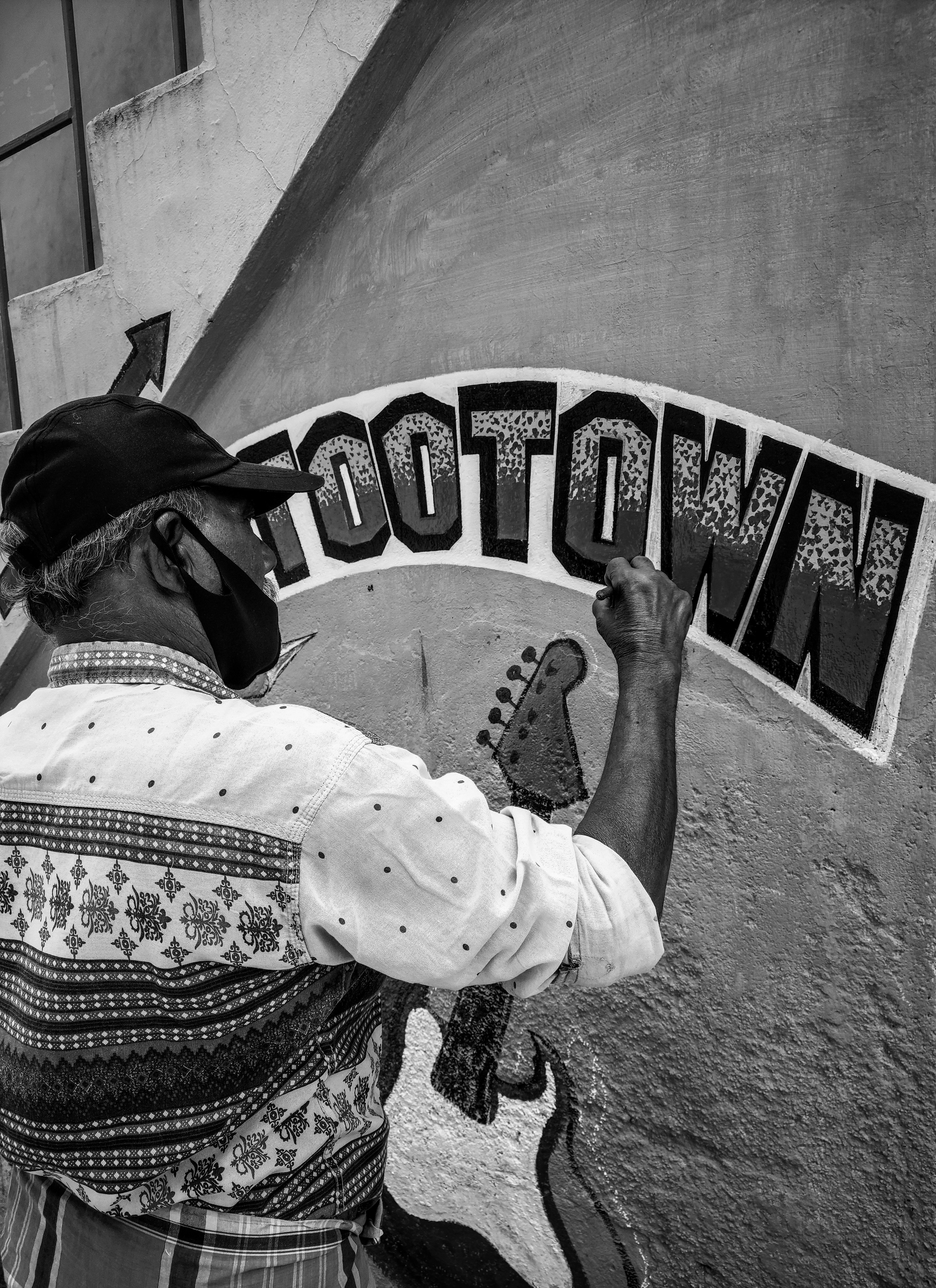 Artist painting the word 'Footown' on a mural, showcasing cultural expression and creativity.