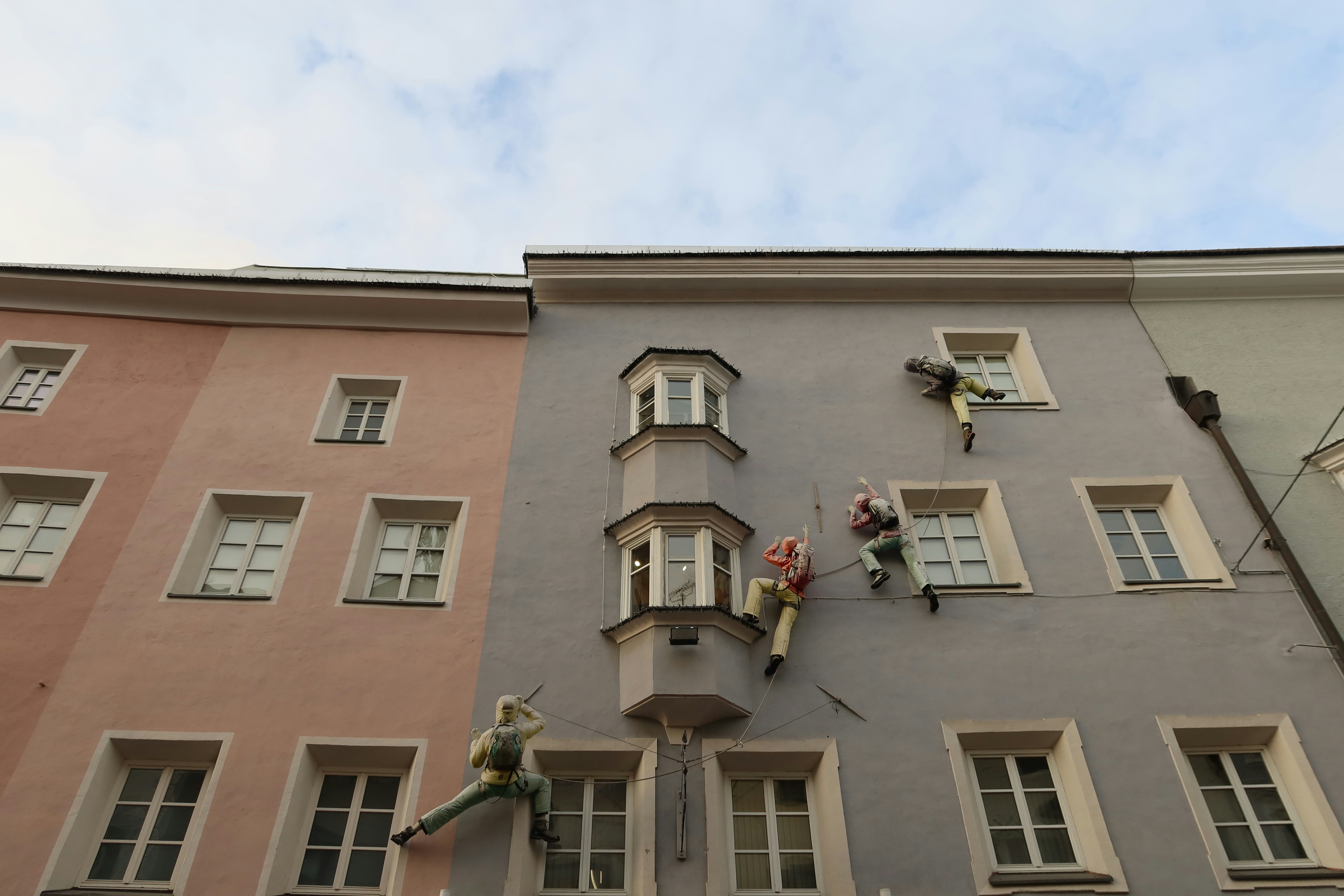 Pastel Facade Play: Climbers Grip the Windows of a City Townhouse