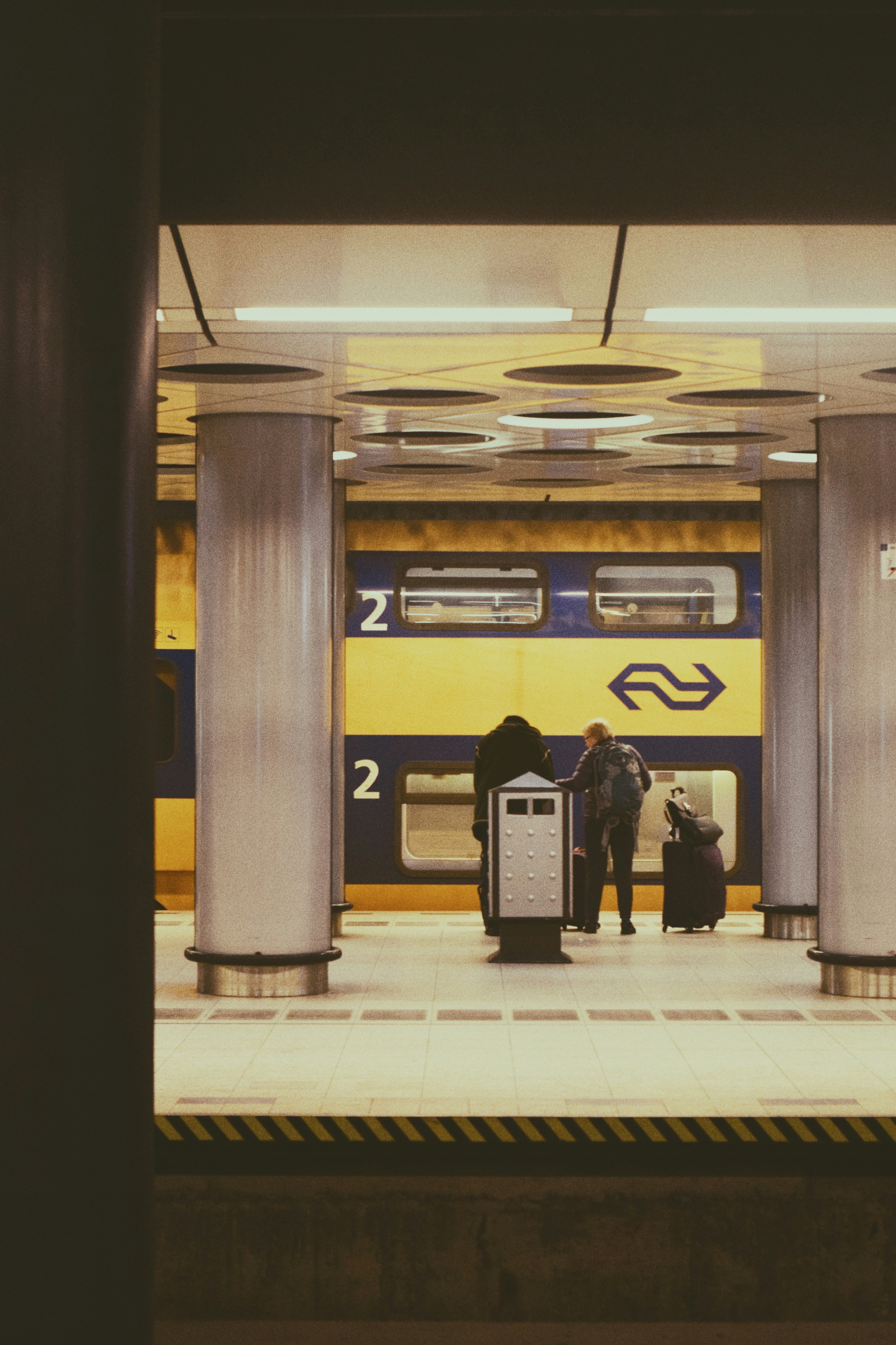 Two-Deck Train at a Quiet Platform: Travelers with Luggage