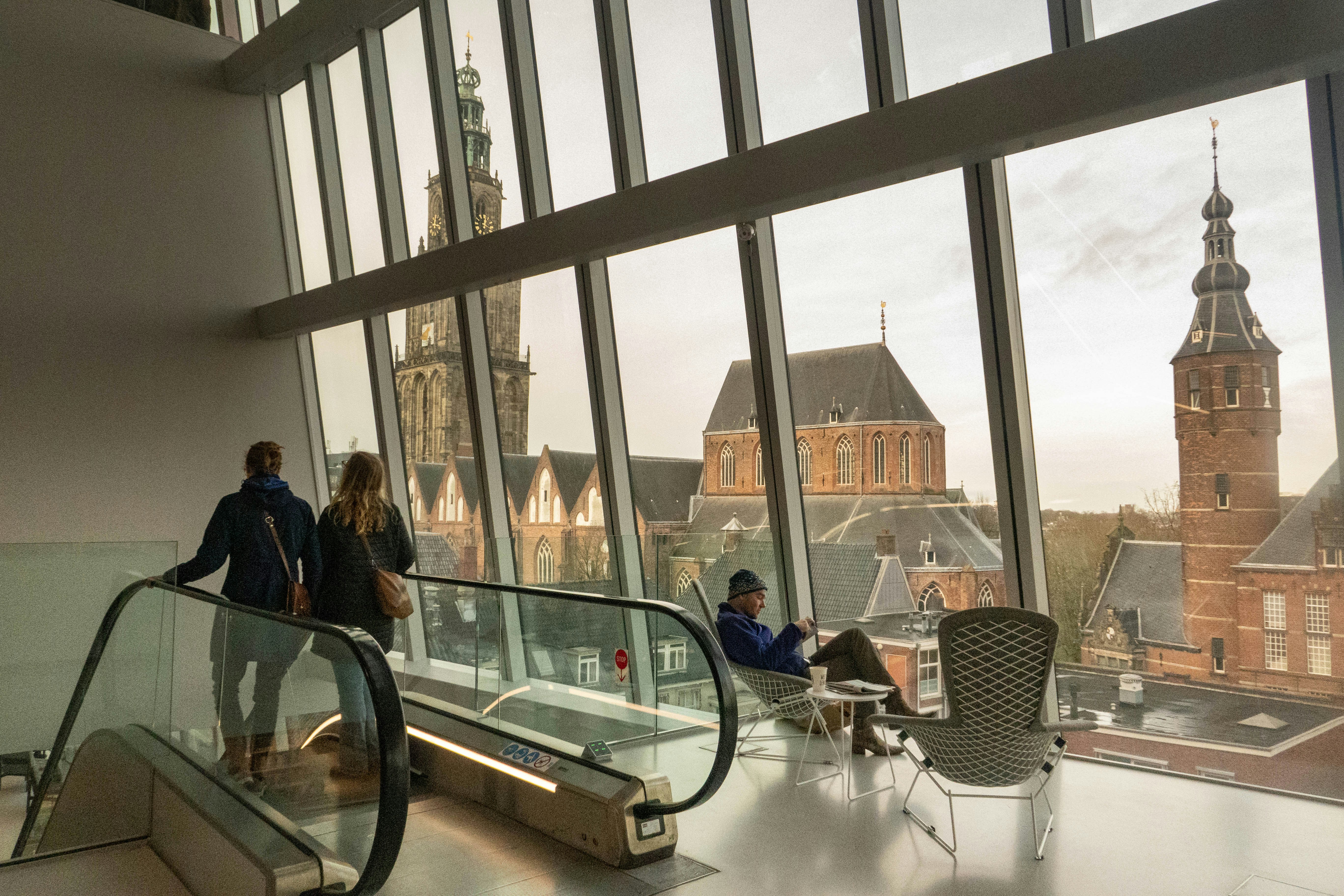 A group of people standing around an escalator in a building photo ...