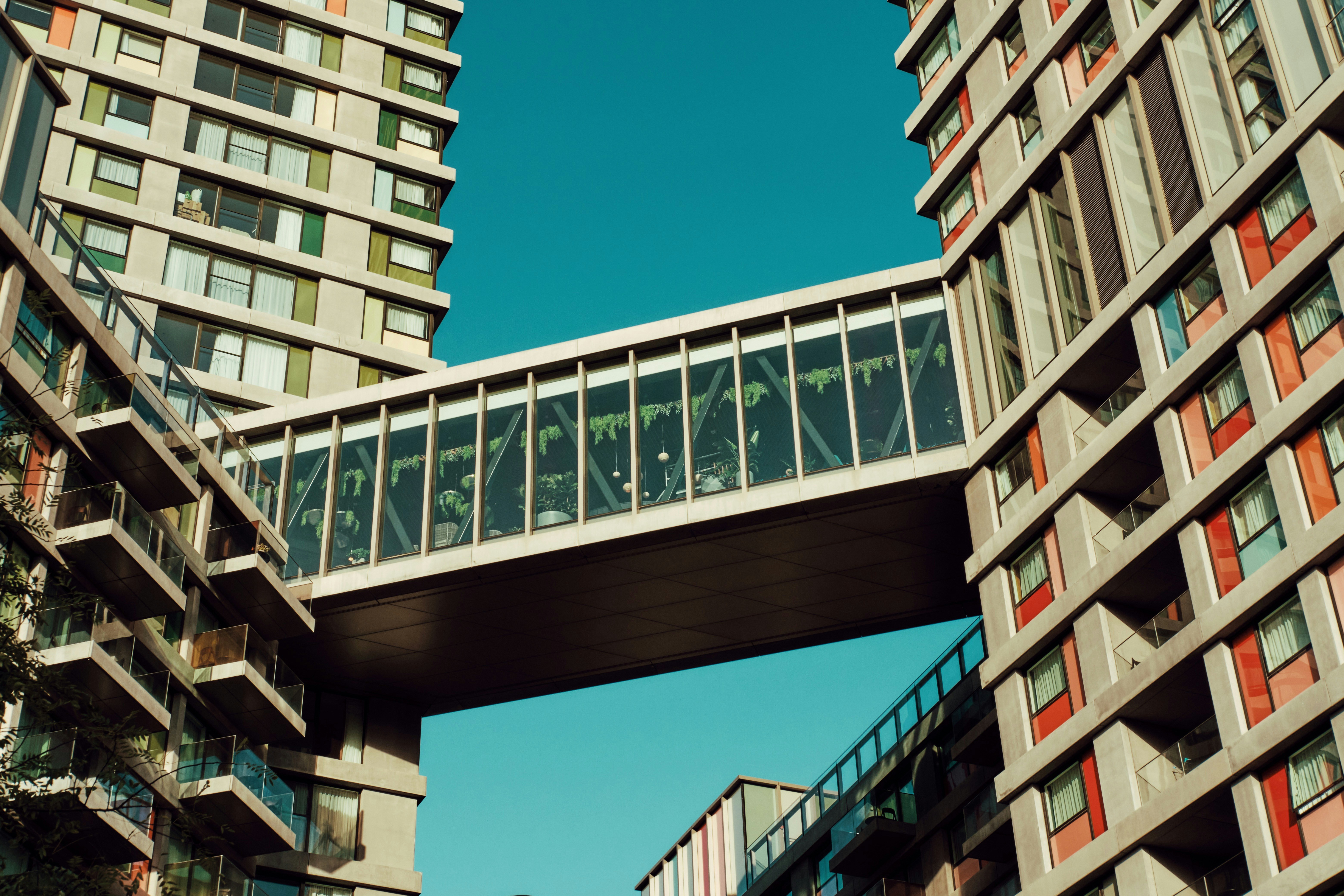 A very tall building with a bridge going over it photo – Free Building ...