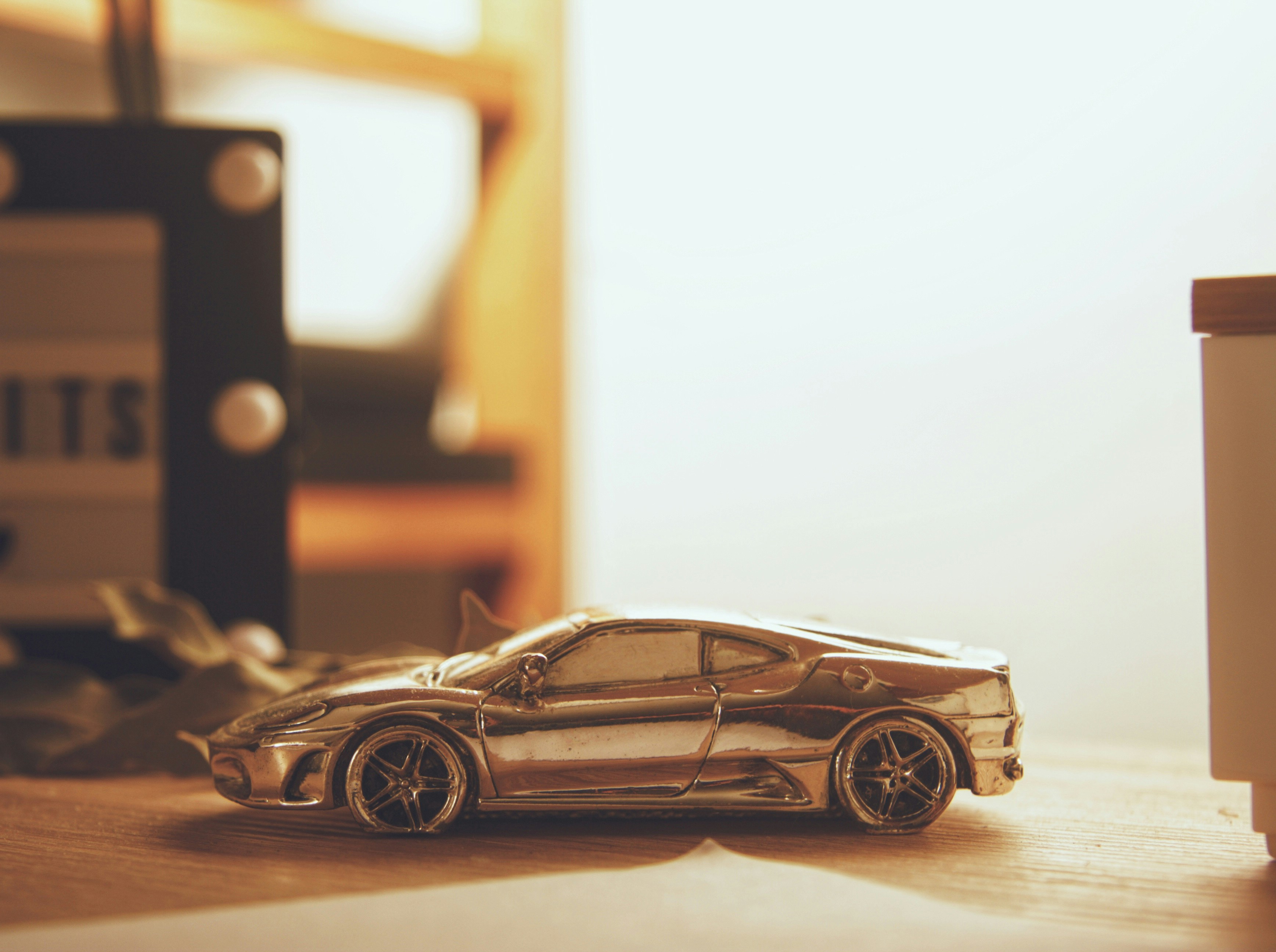Metallic toy car displayed on a wooden table with soft lighting.