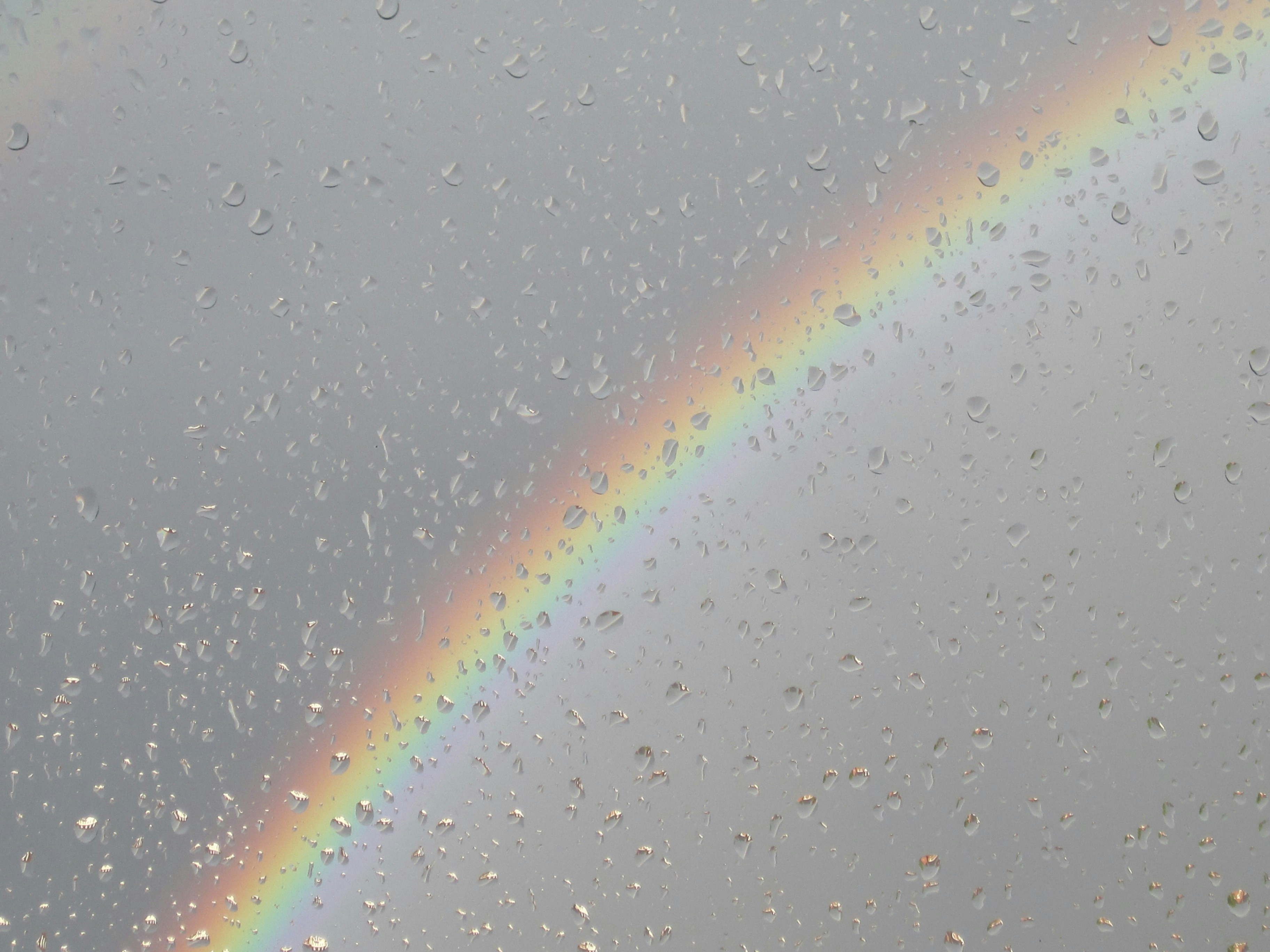 A rainbow is seen through the rain on a window photo – Free Rain Image ...