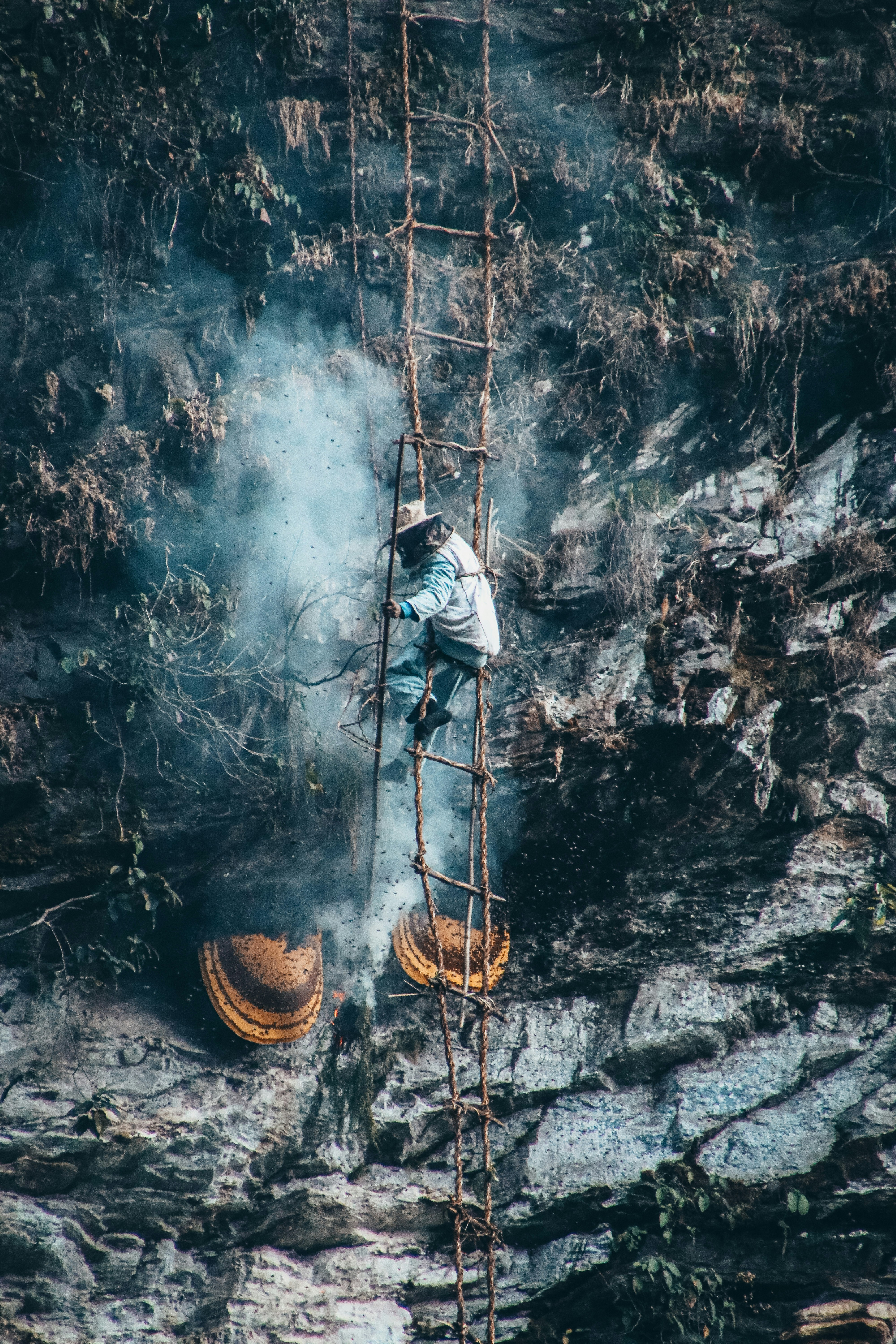 Mist-Wreathed Ascent: A Climber Clings to a Rope Ladder on a Rugged Cliff