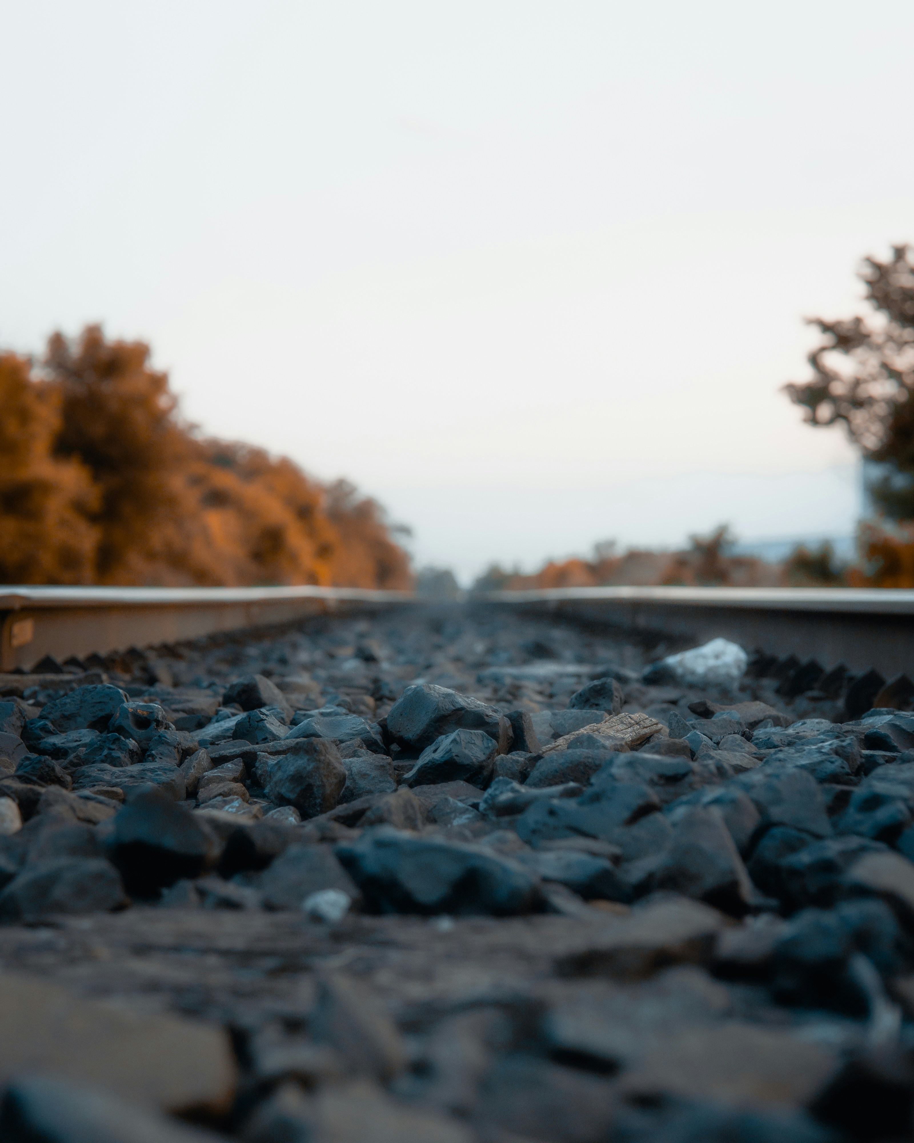 A train track with rocks and trees in the background photo – Free ...