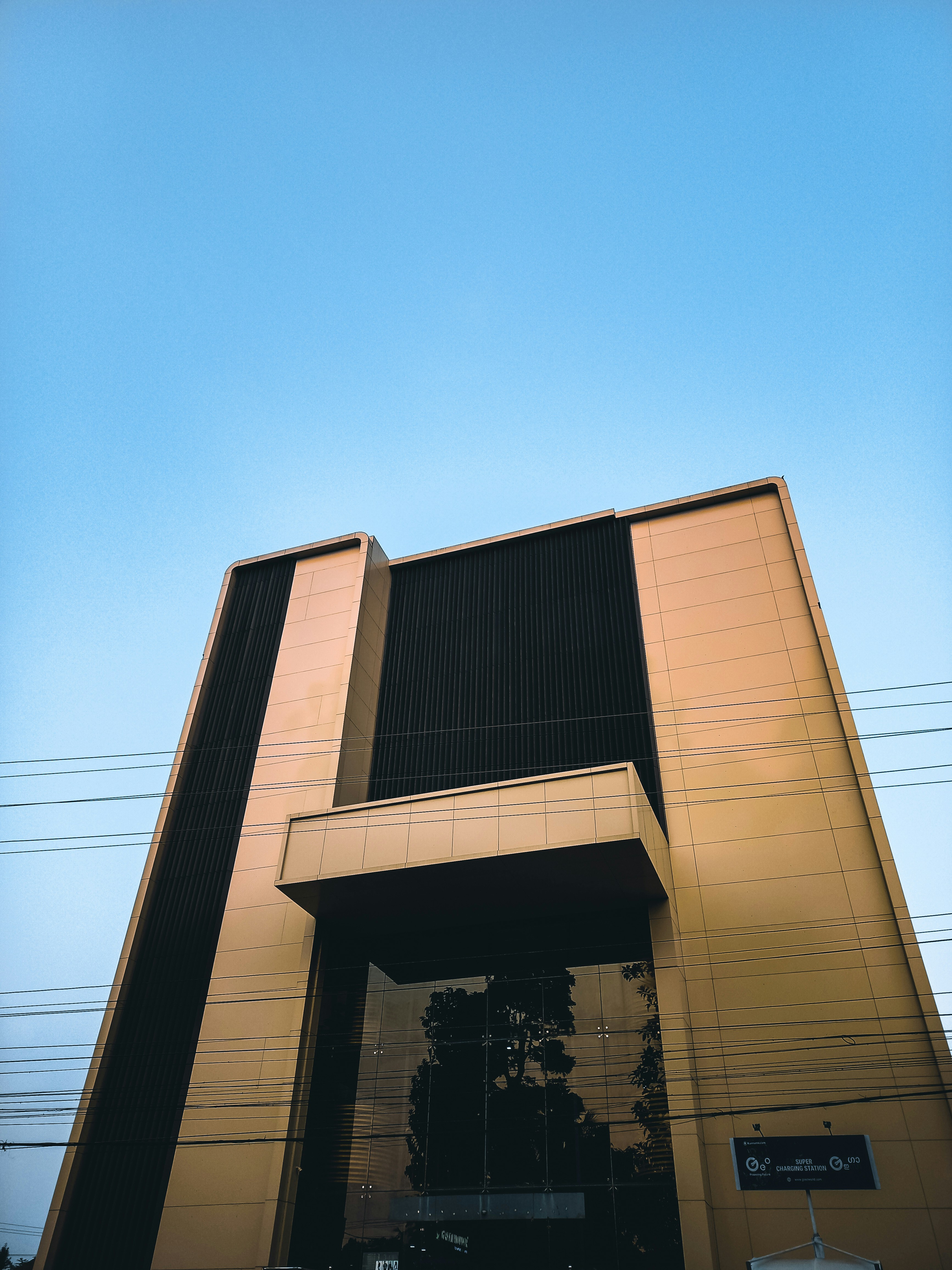 Sleek golden building with vertical black lines under a clear blue sky, showcasing contemporary design elements.