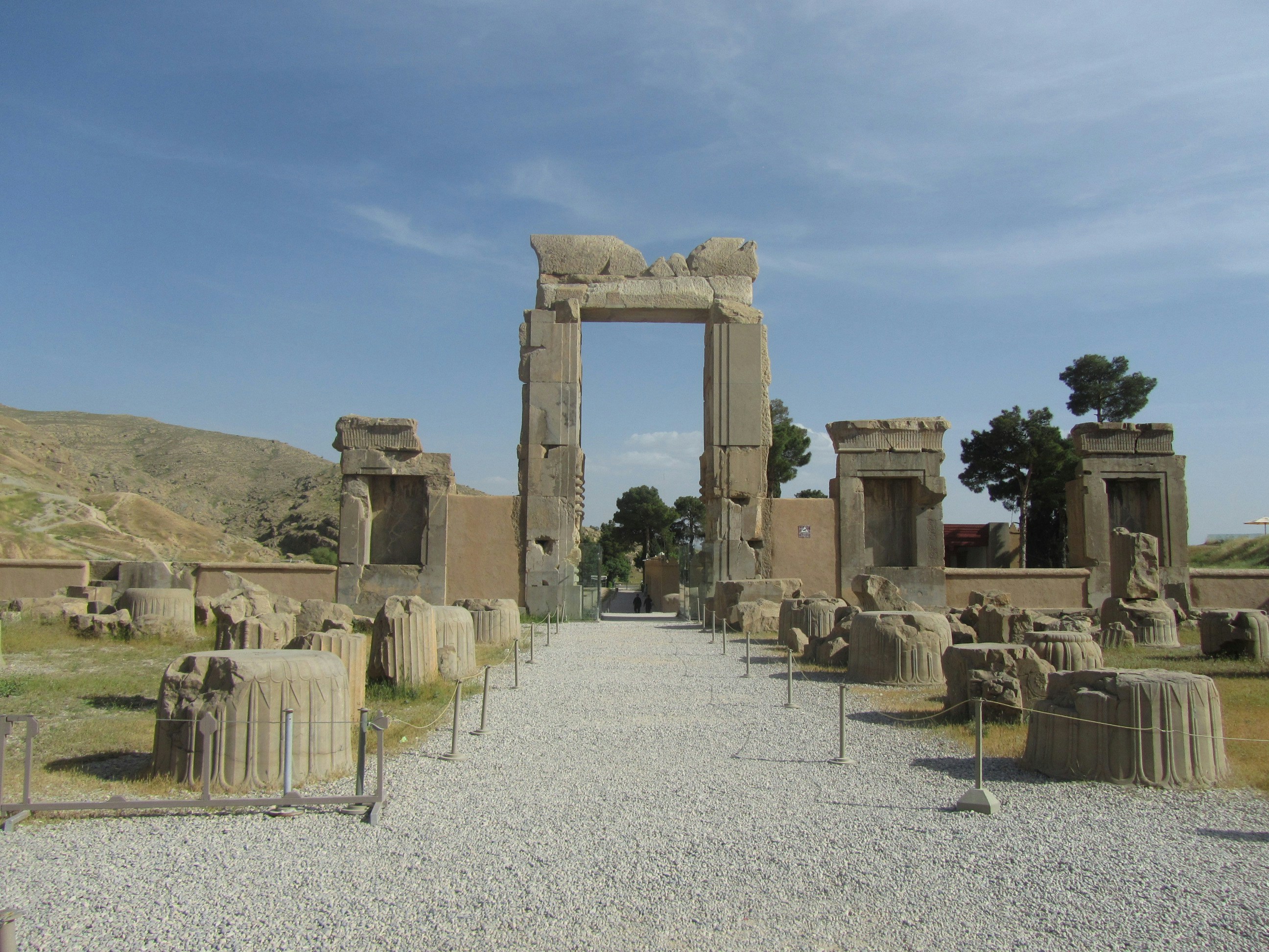 Stone archway surrounded by historical ruins under a clear blue sky.