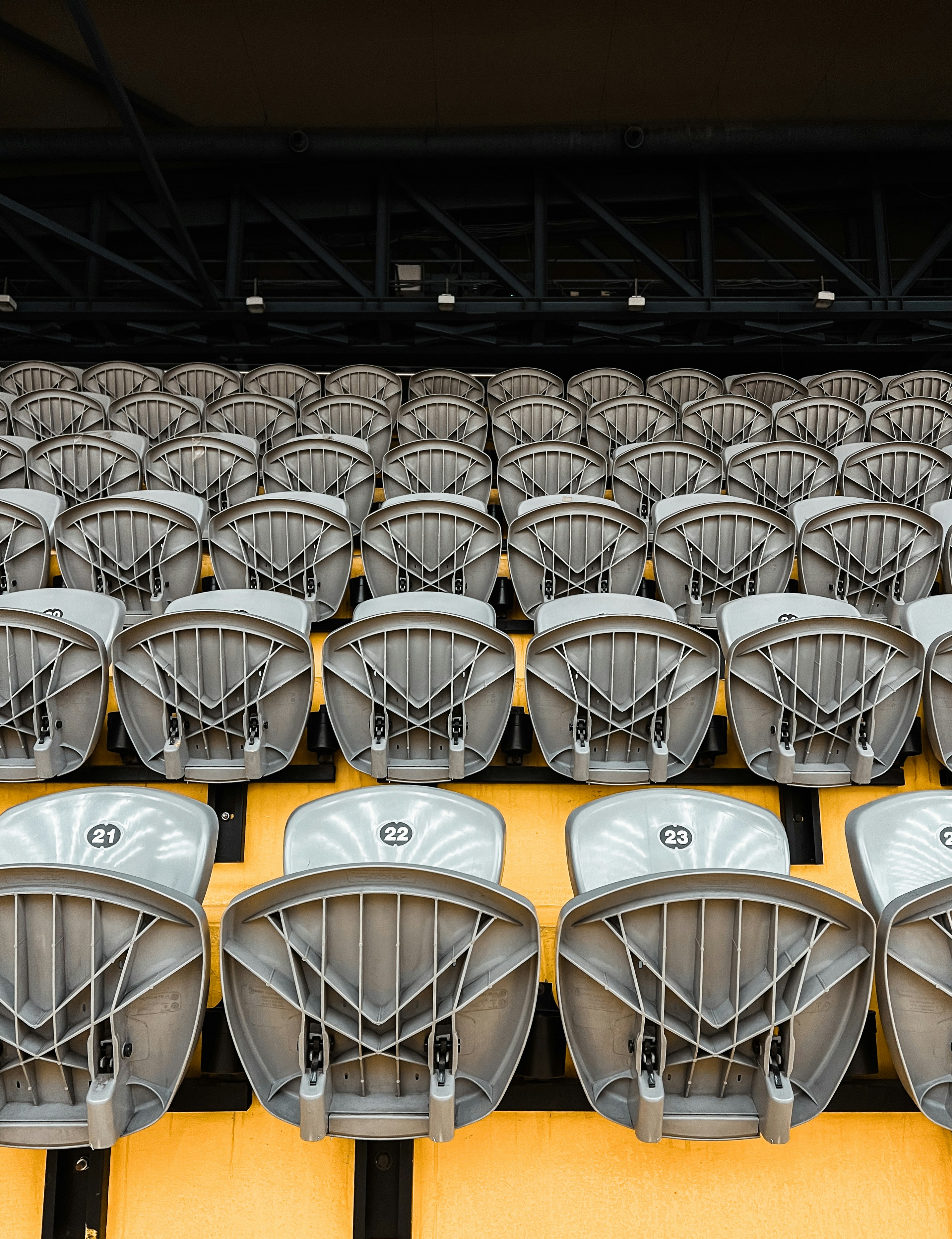 Rows of empty stadium seats arranged in a precise pattern, highlighting their minimalist design and functionality.