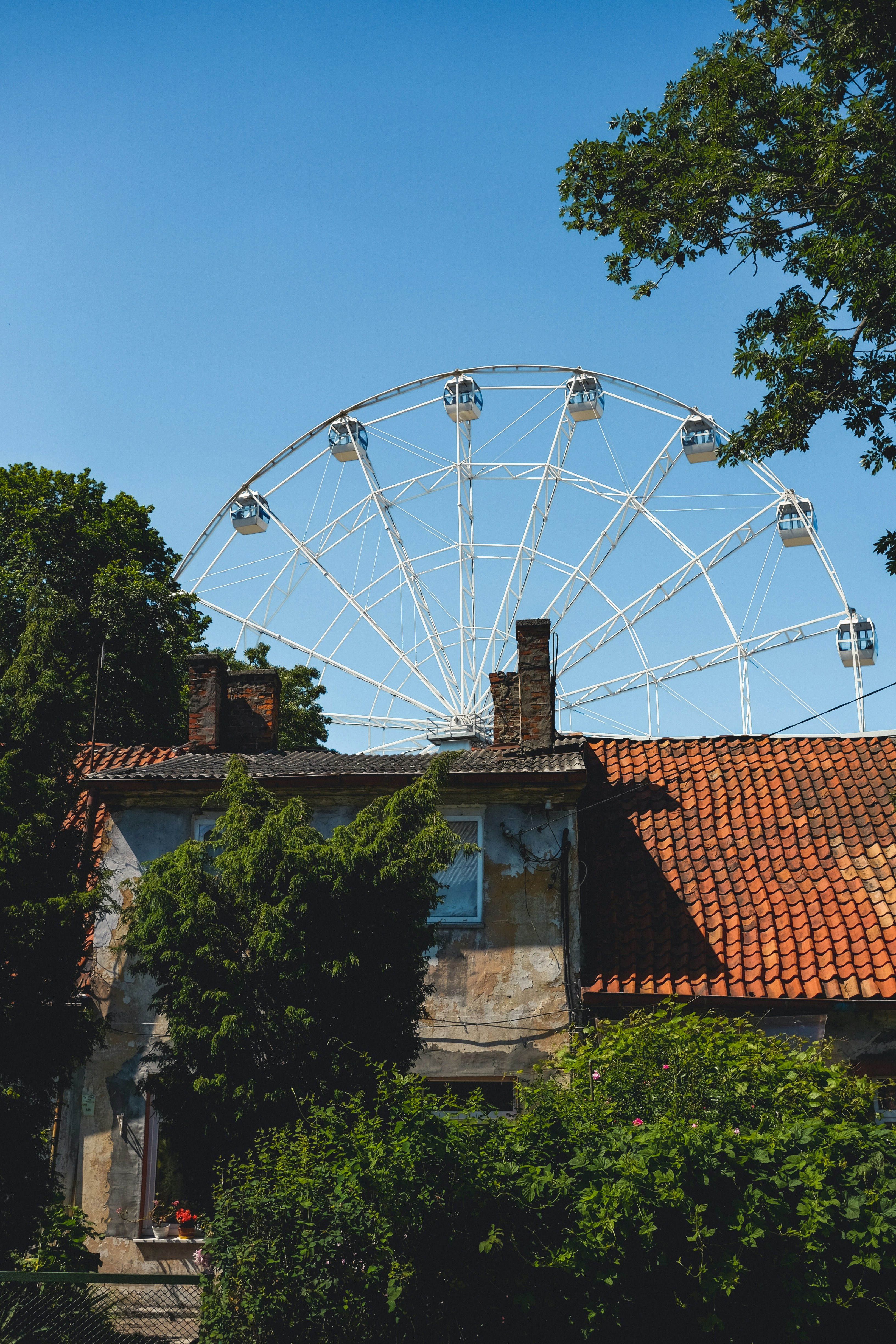 Ferris Wheel Rising Behind a Weathered Red-Tiled Roof