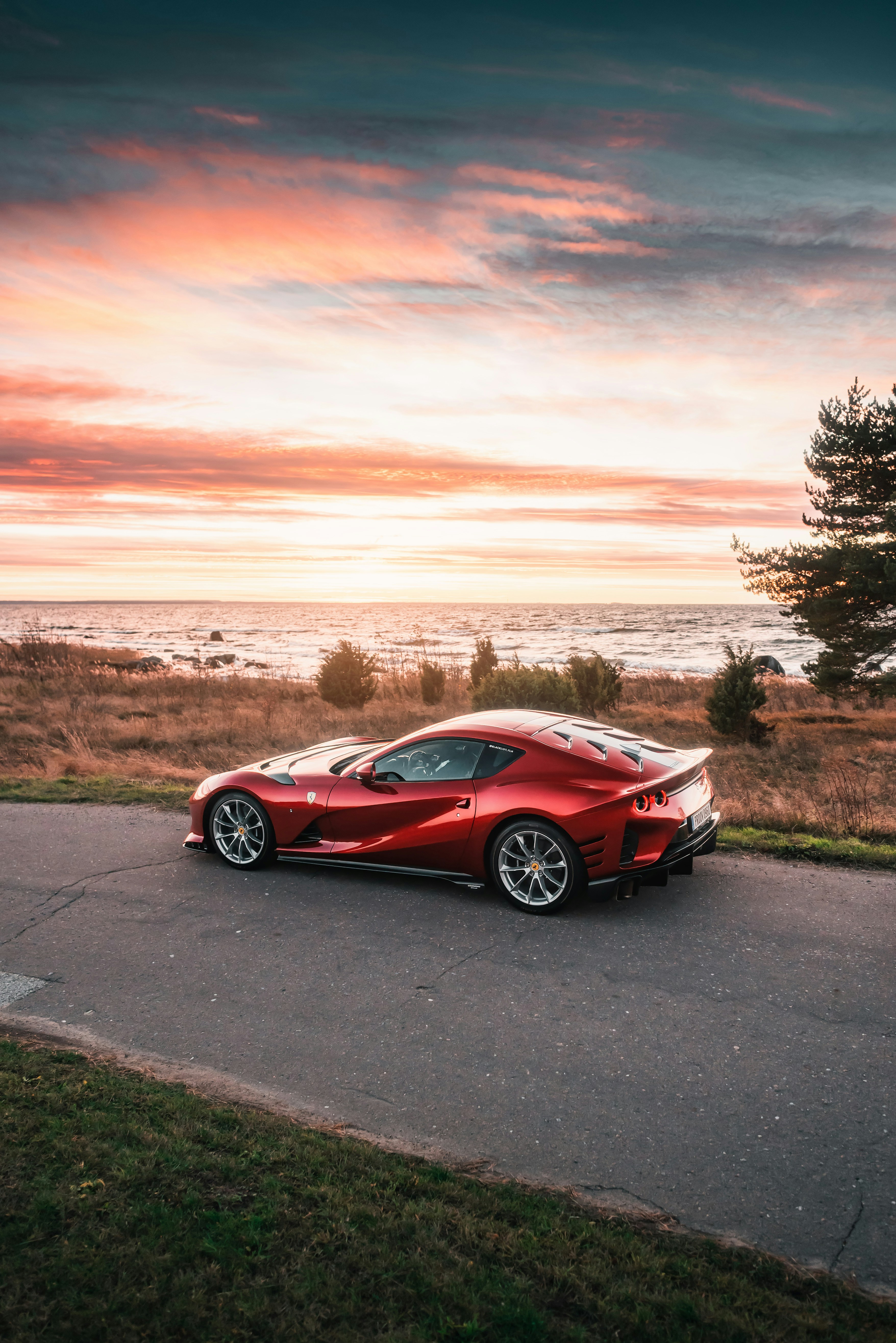 Red midengine: sunset silhouette of a hypercar by the lakeside road