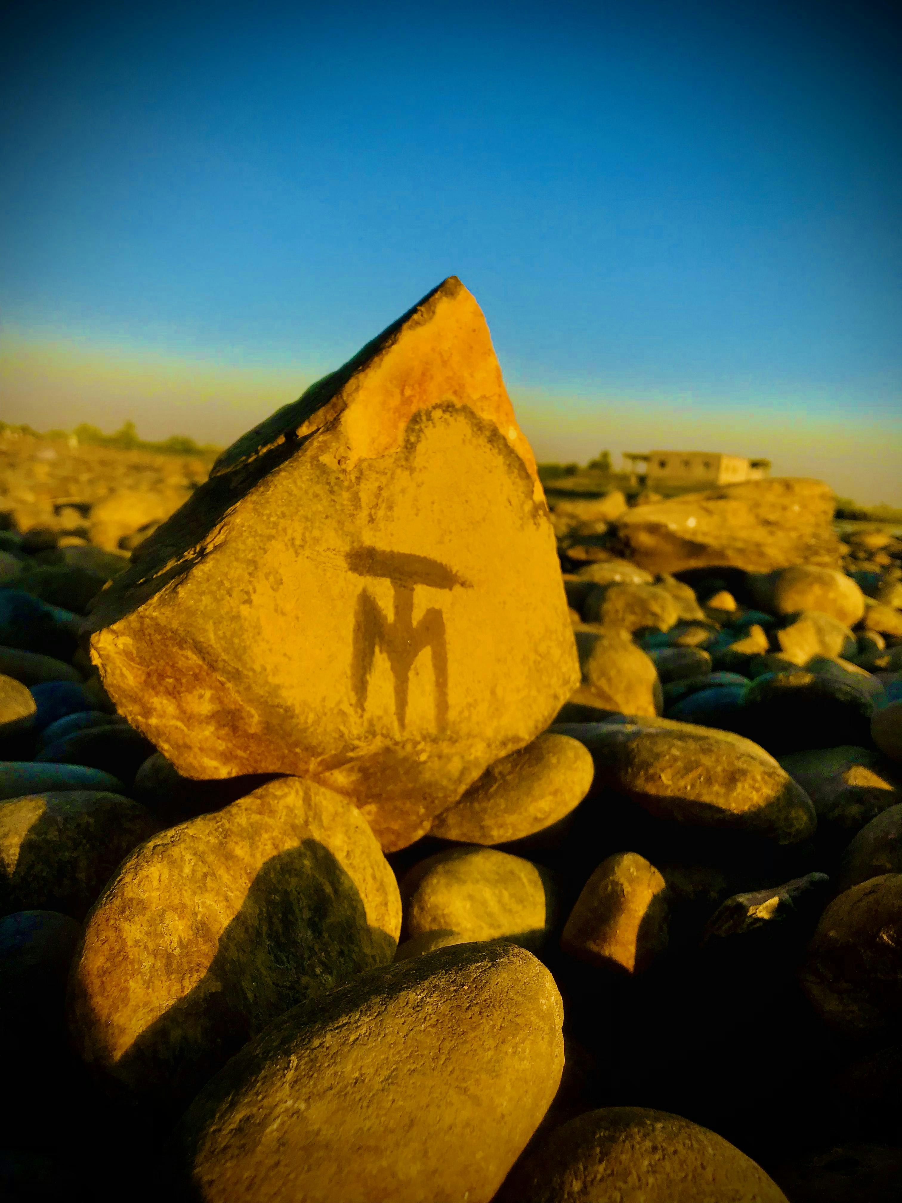 Glyph in the Pebble Sea: A Sunlit Rock Marked with Mystery