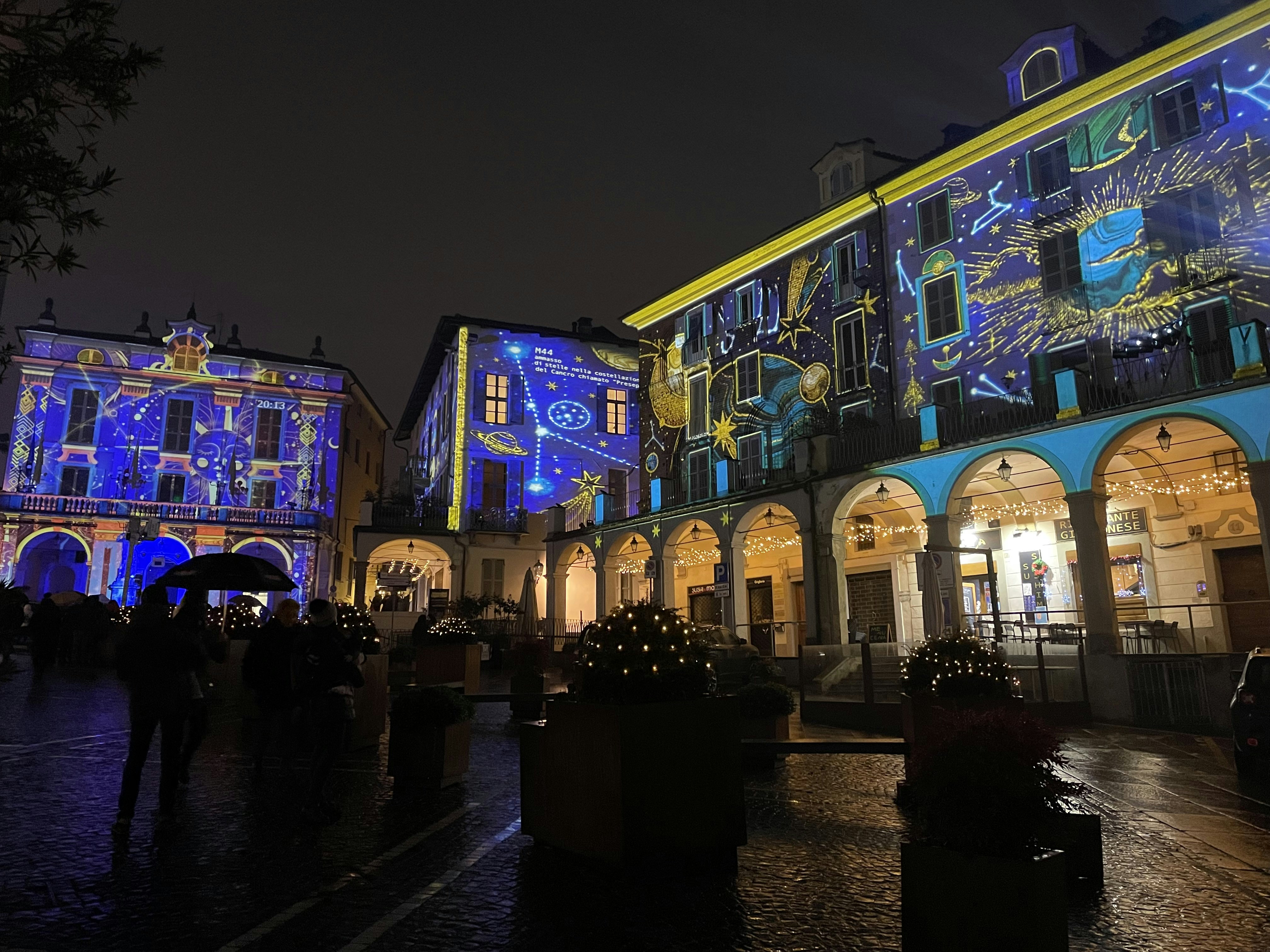 Colorful projections light up historic buildings at night, creating a vibrant urban scene.