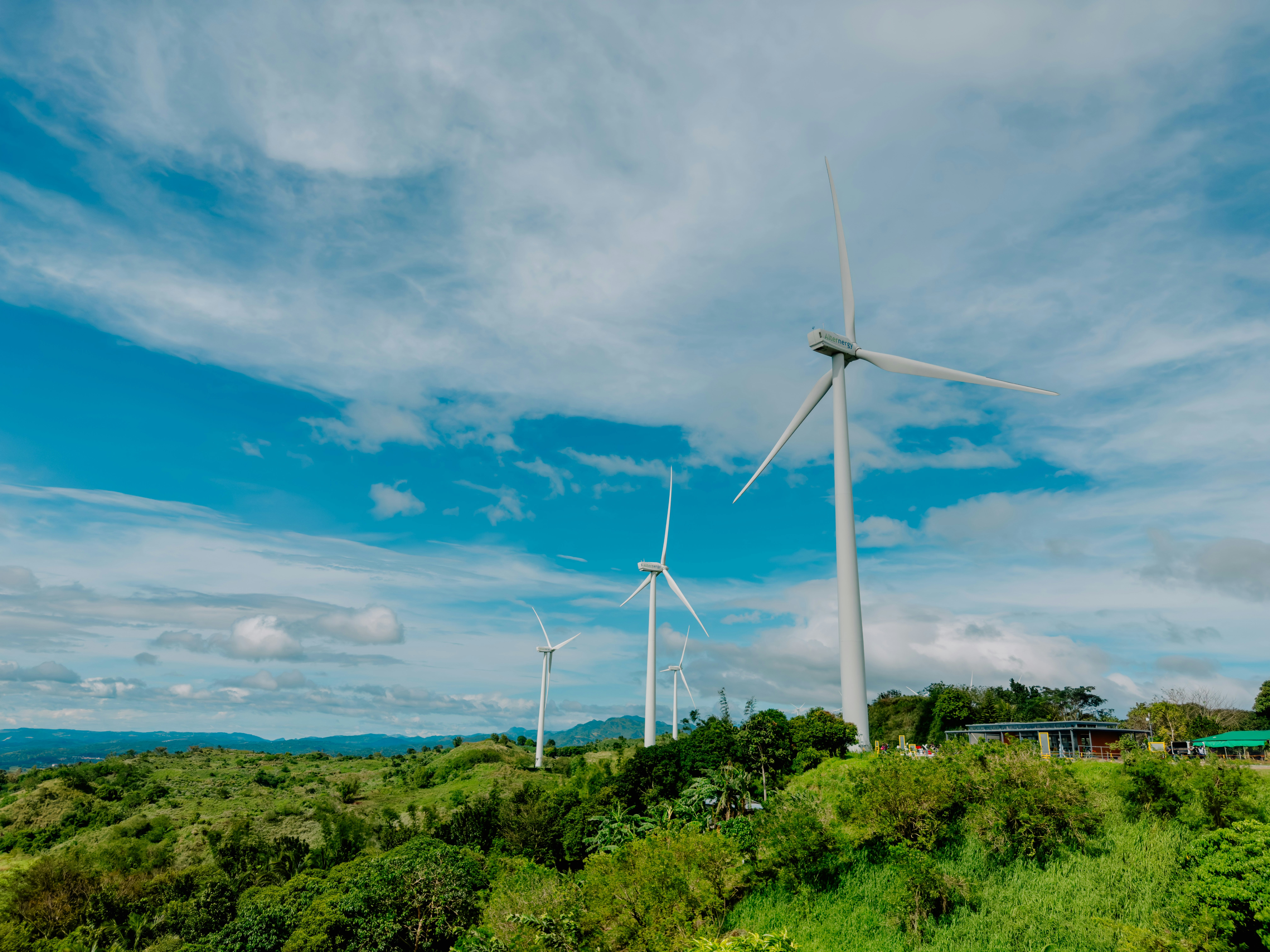 Giant Wind Turbines Crown a Rolling Green Ridge Under a Crisp Blue Sky