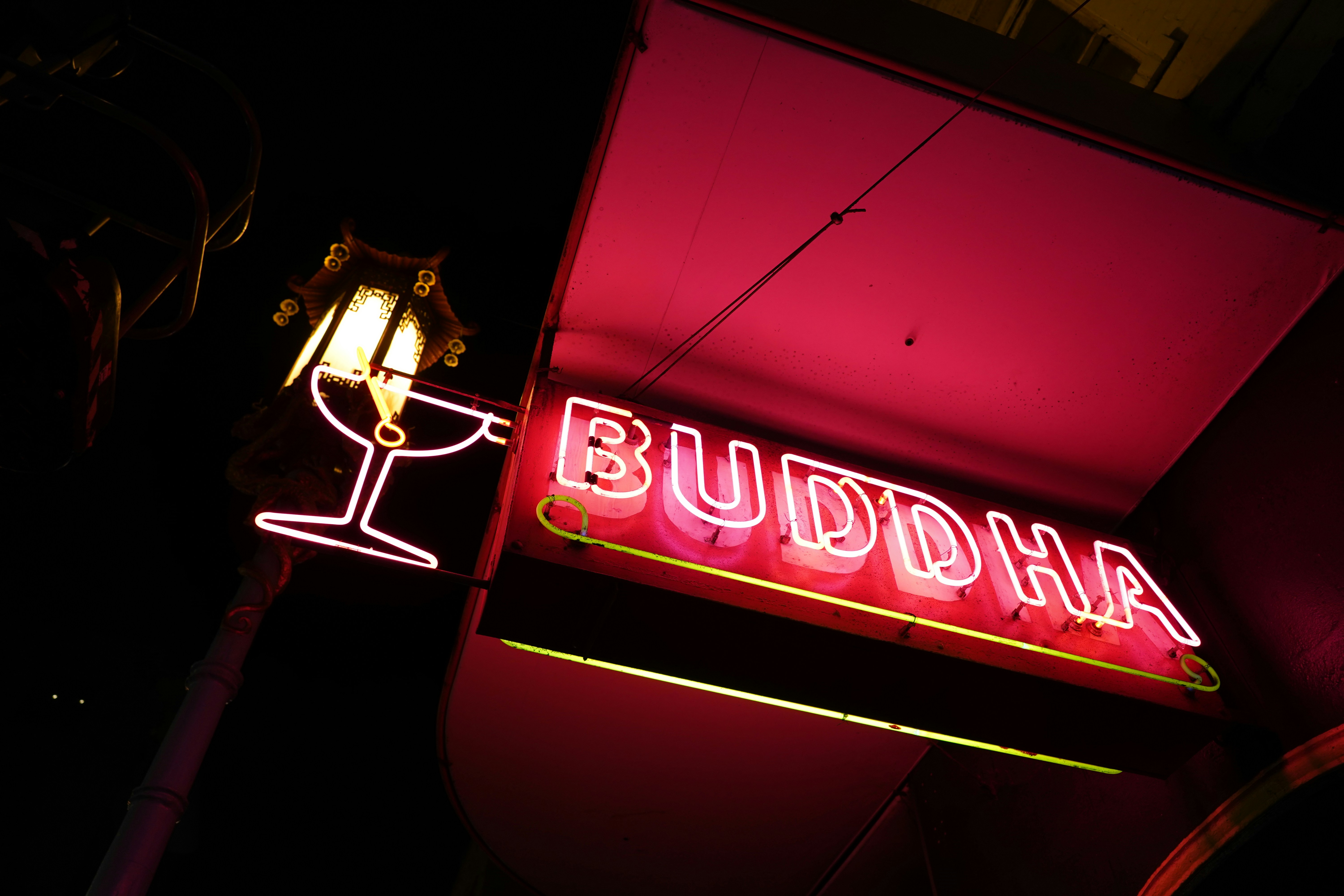 Crimson Neon Buddha Sign Looms Over a Quiet Night Street