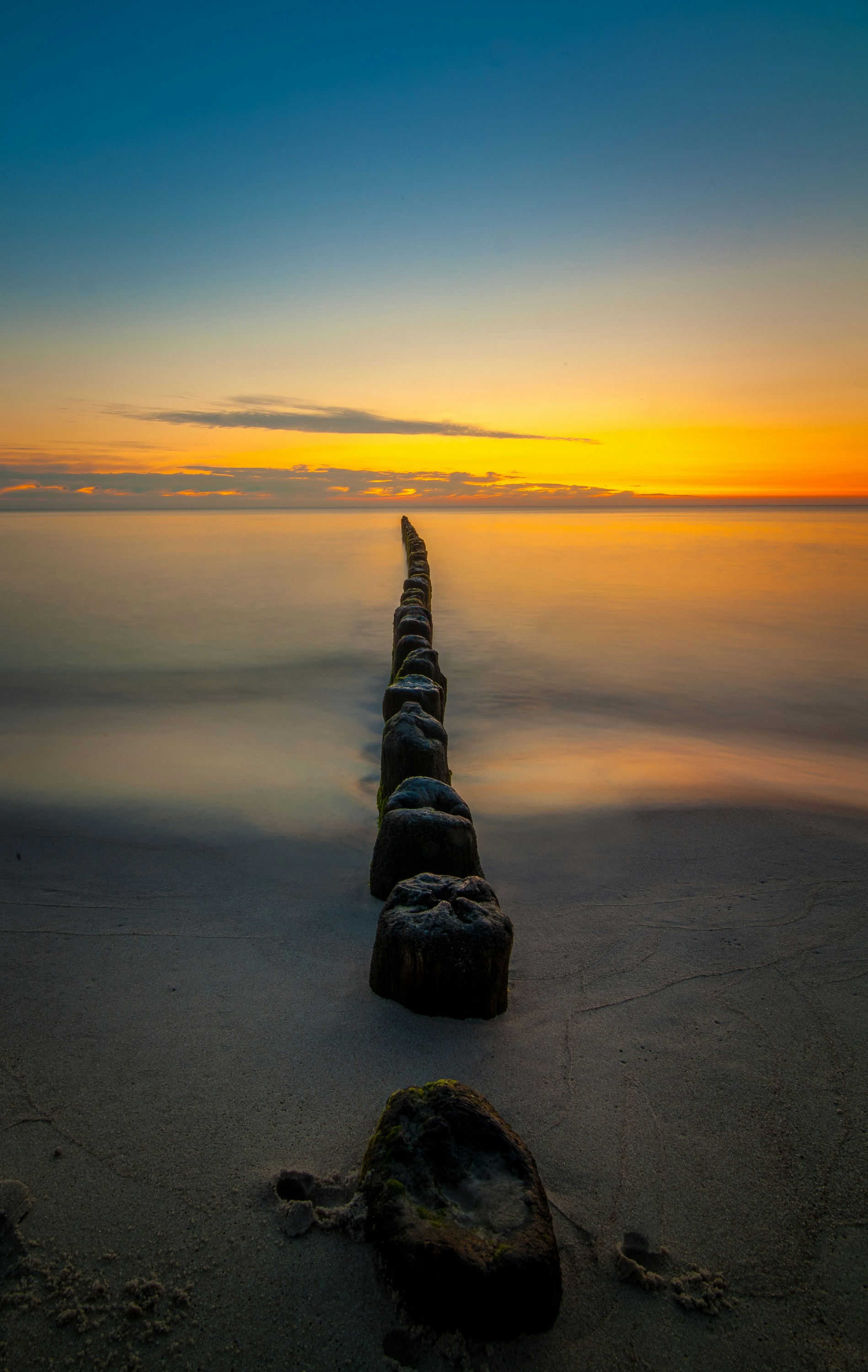 A long line of rocks sitting on top of a beach photo – Free Sunrise ...