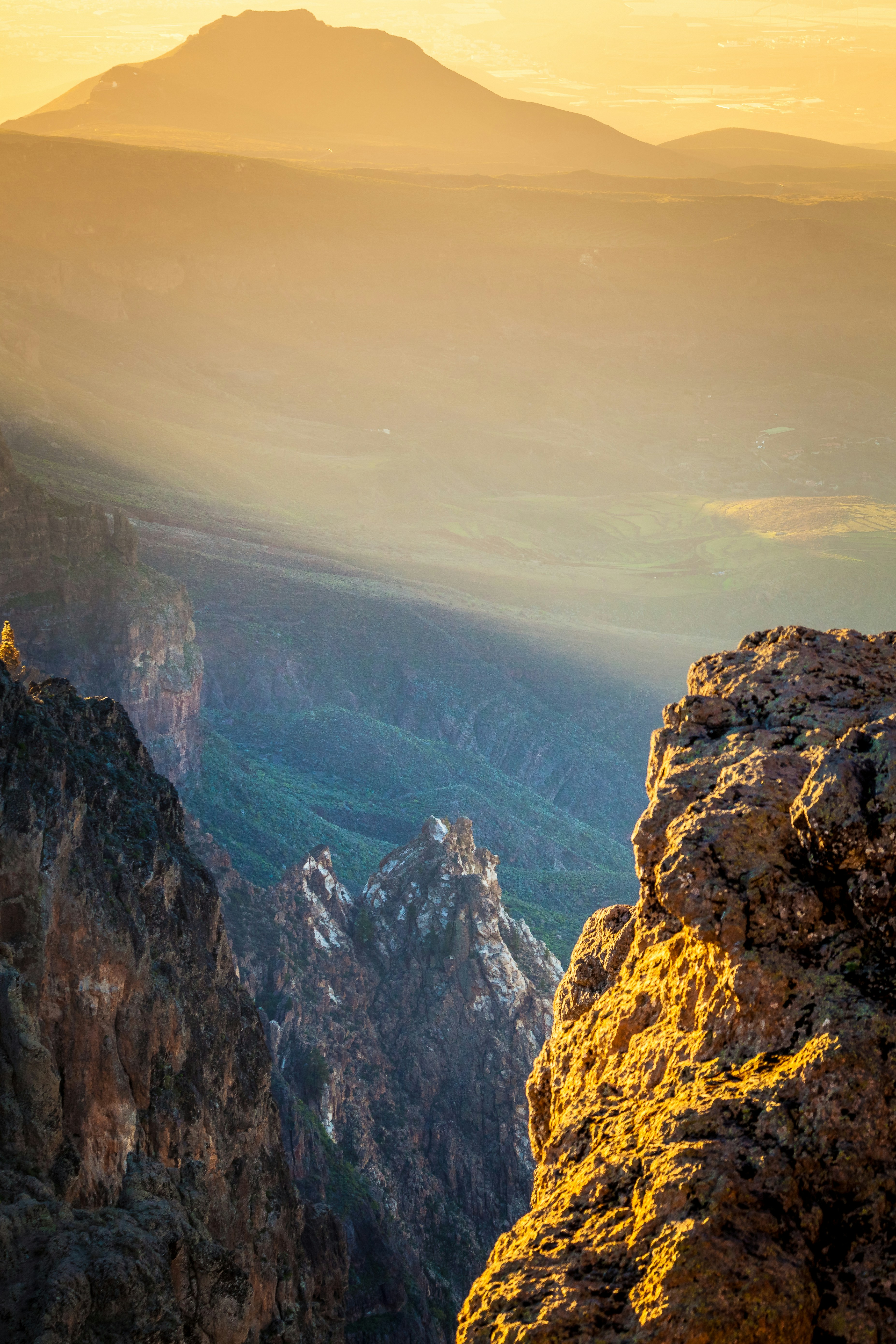 A man sitting on top of a mountain overlooking a valley photo – Free ...