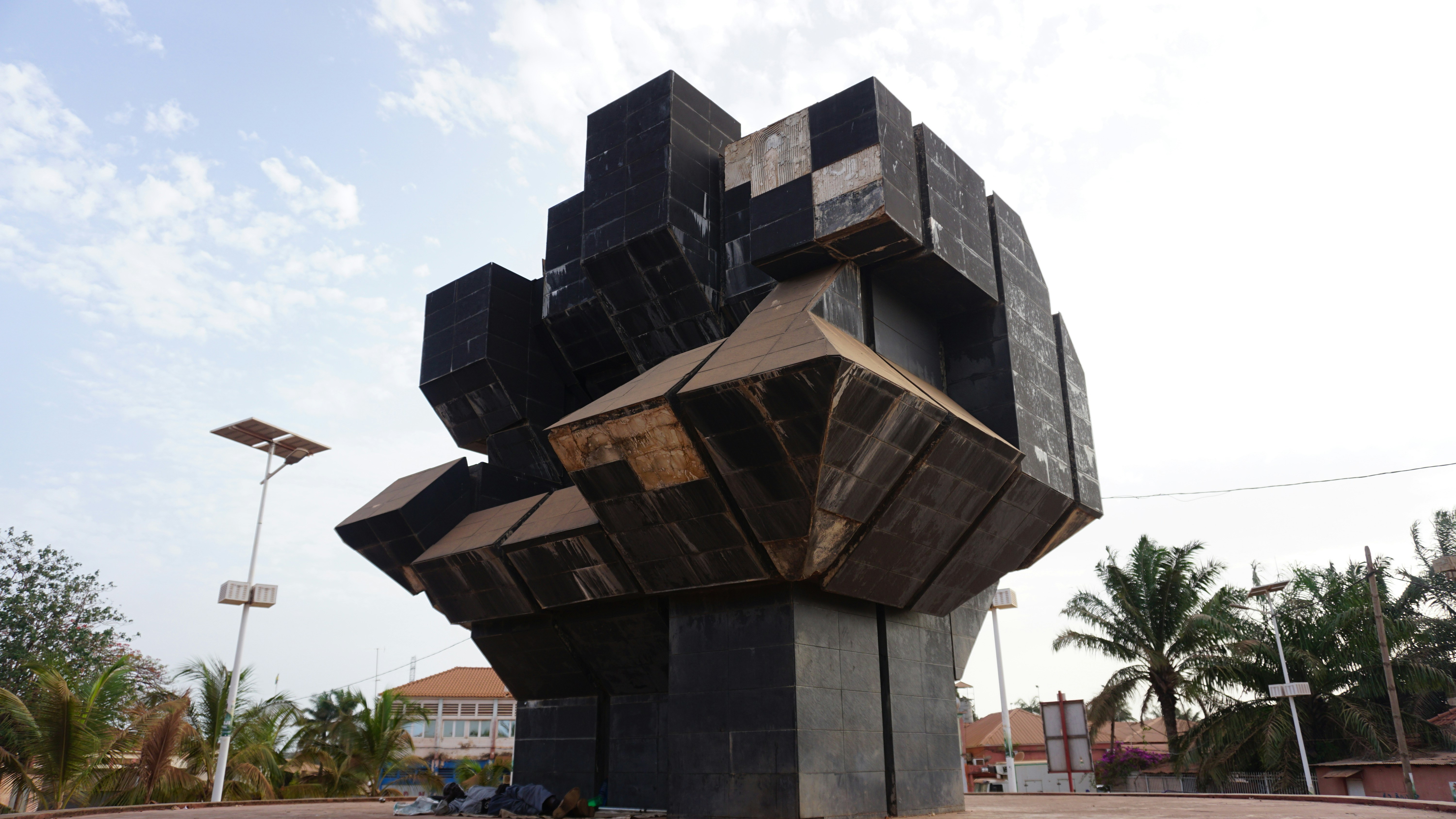 A large sculpture made of black boxes sitting on top of a cement block ...