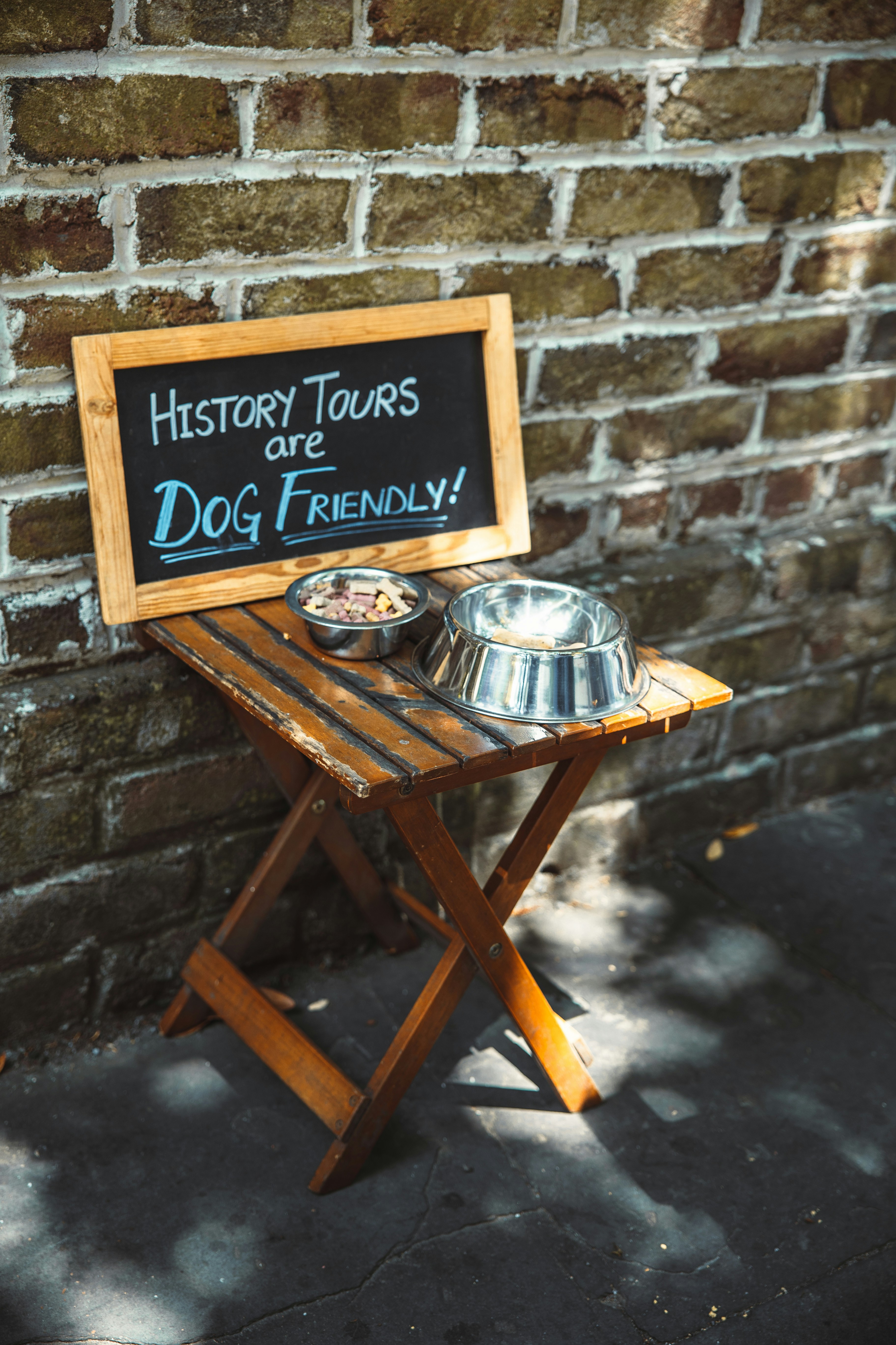 a wooden table with a sign and a dog dish on it