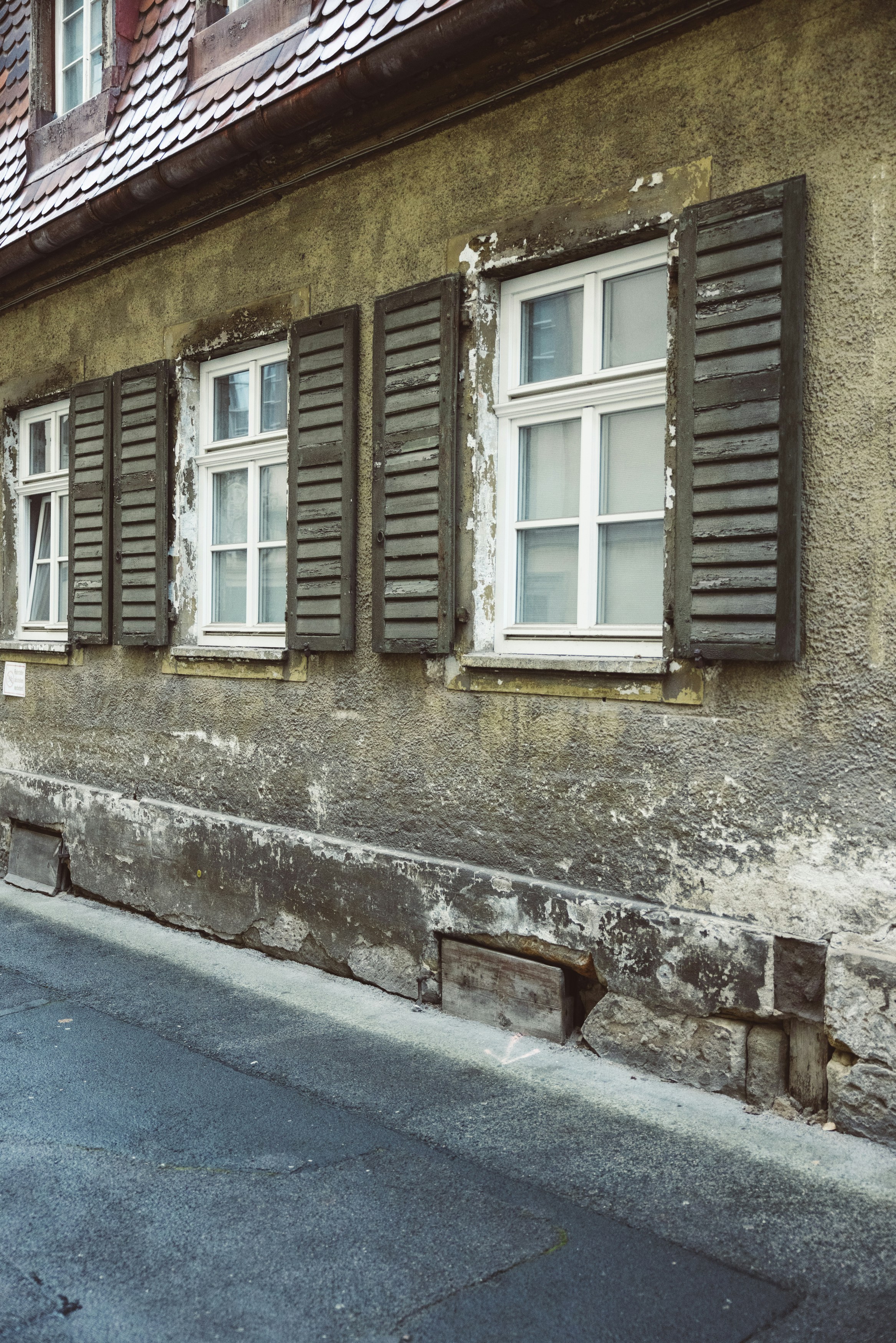 Weathered Facade: Three Shuttered Windows and the Texture of Time