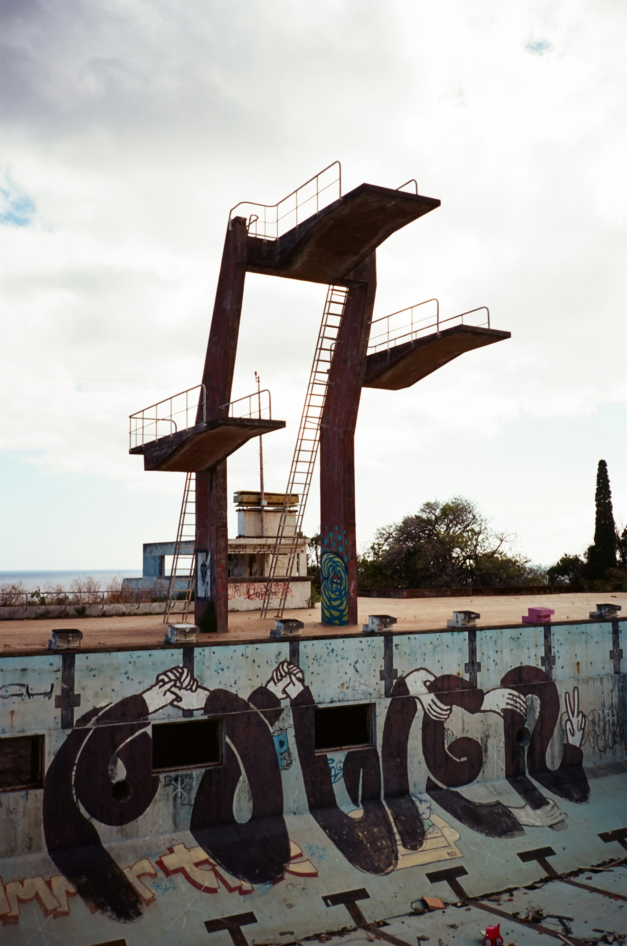 Rust-Lit Sentinel: Abandoned Dive Tower Over Graffiti-Coated Concrete