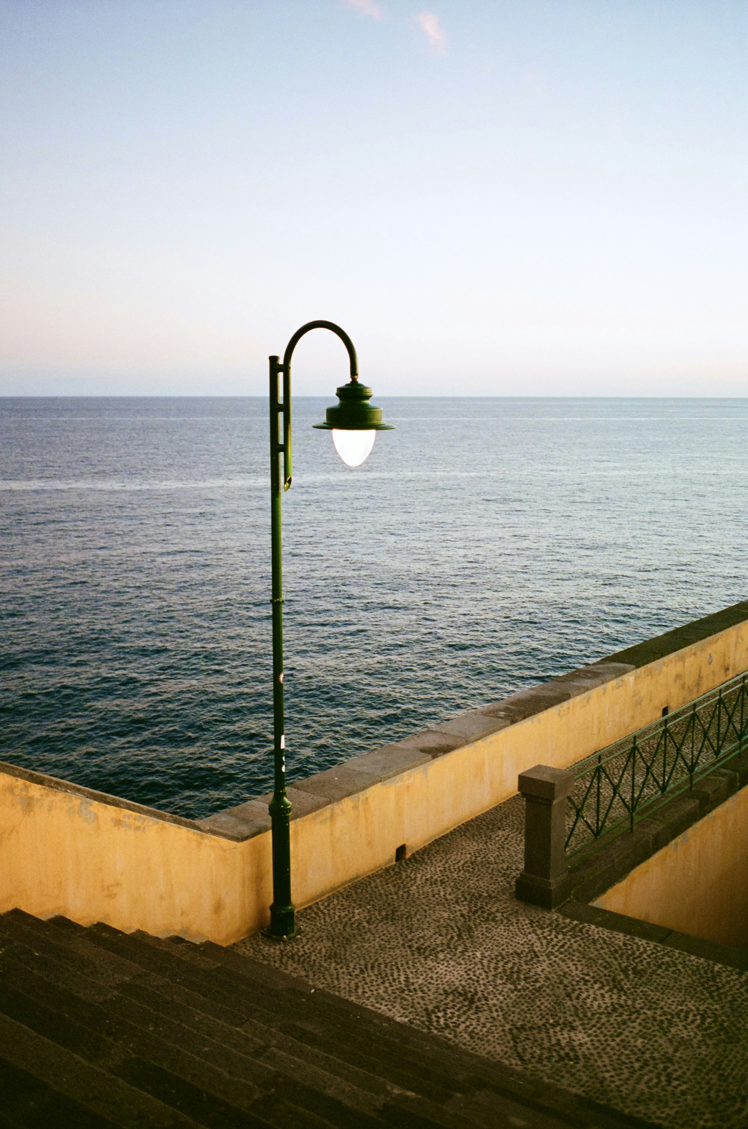A street light sitting on the side of a wall next to the ocean photo ...