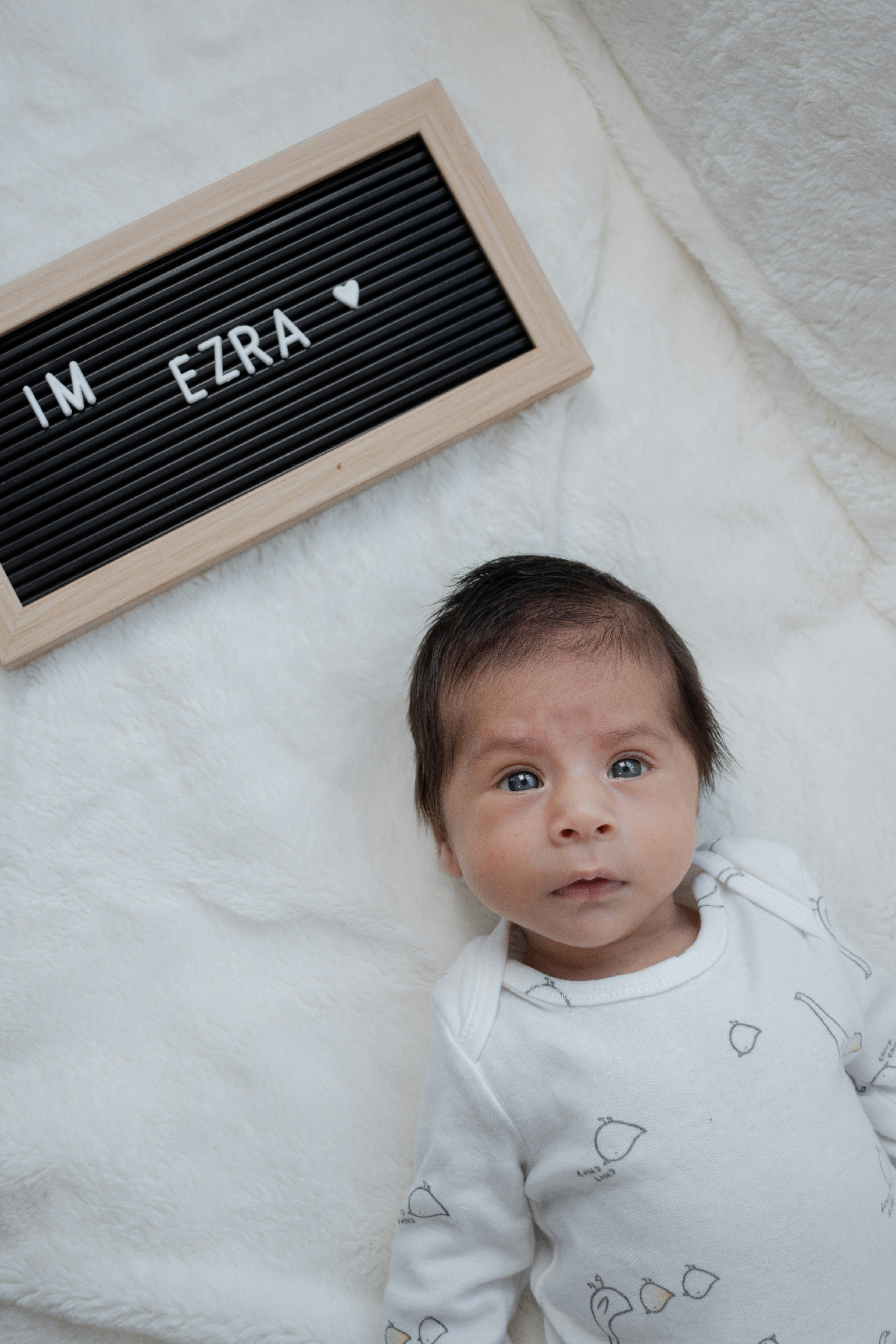 Baby Ezra Gazes Up from a Cozy White Backdrop