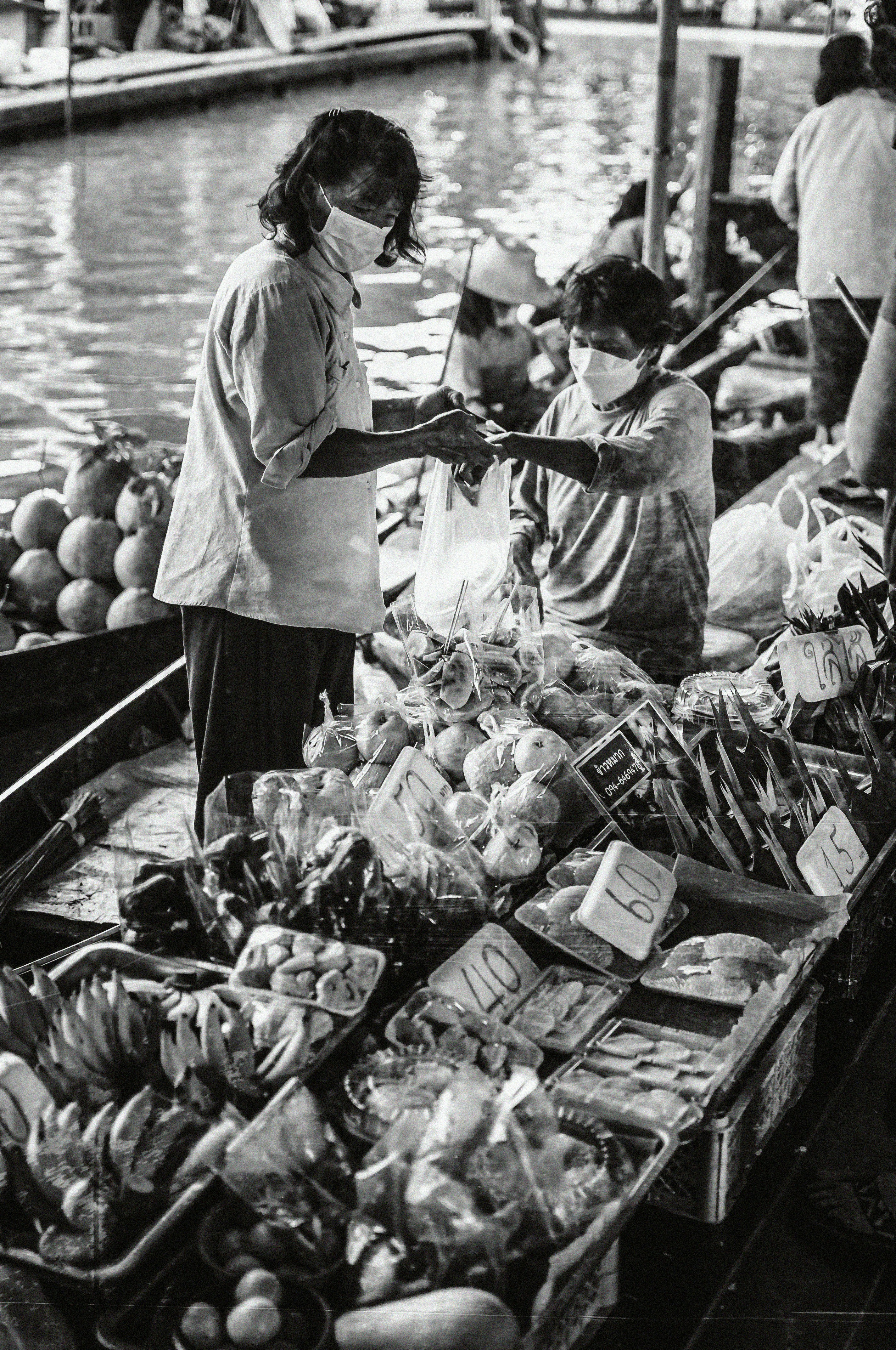 Masked Exchange Over Fresh Produce at a Floating Riverside Market